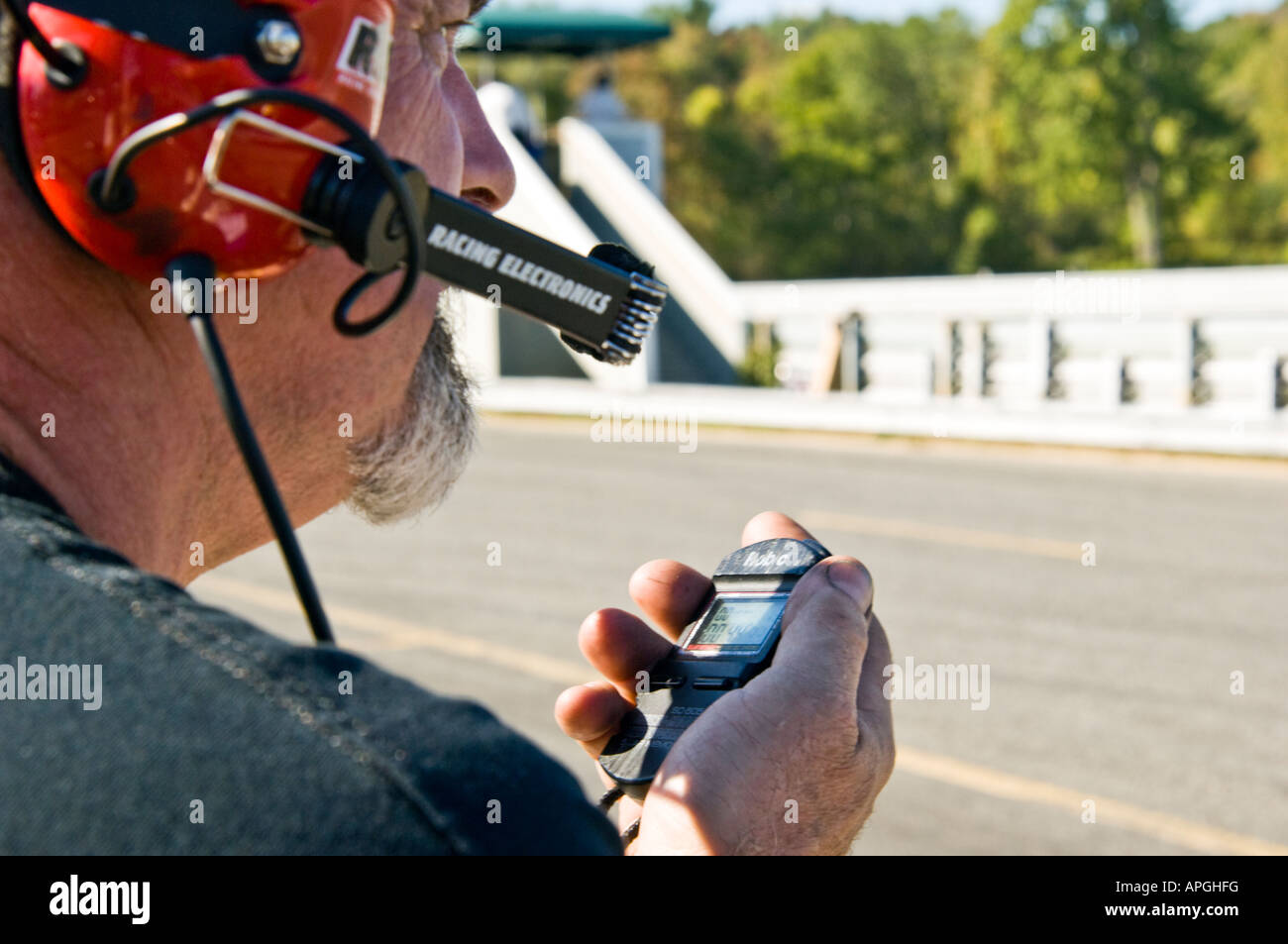 Motor racing team member checks lap times and communicates with driver ...