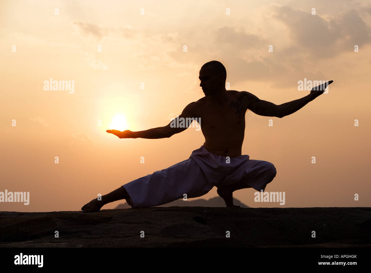 Man performing tai chi against a setting sun in india Stock Photo - Alamy