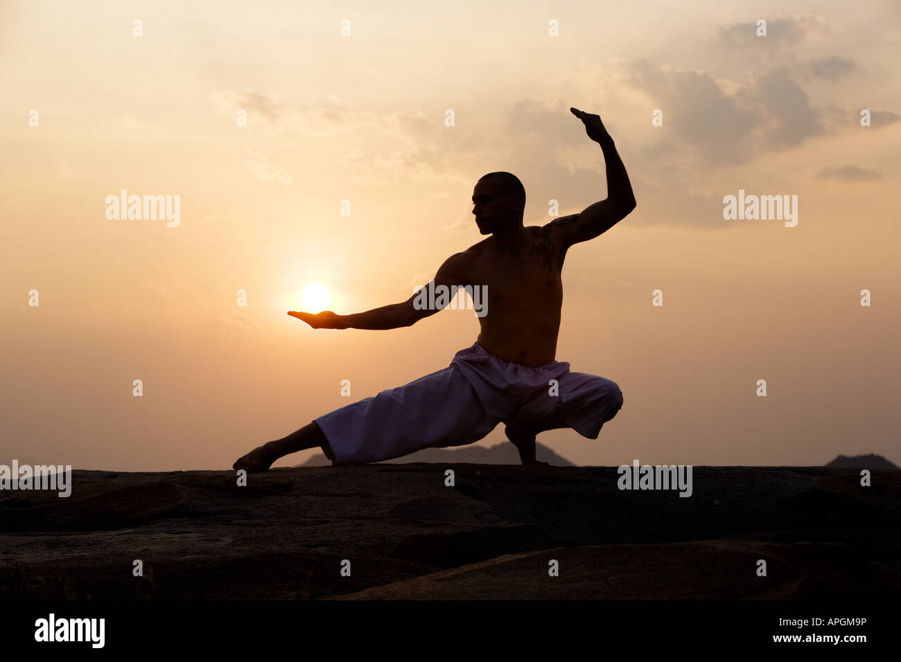 Man performing tai chi against a setting sun in india Stock Photo - Alamy