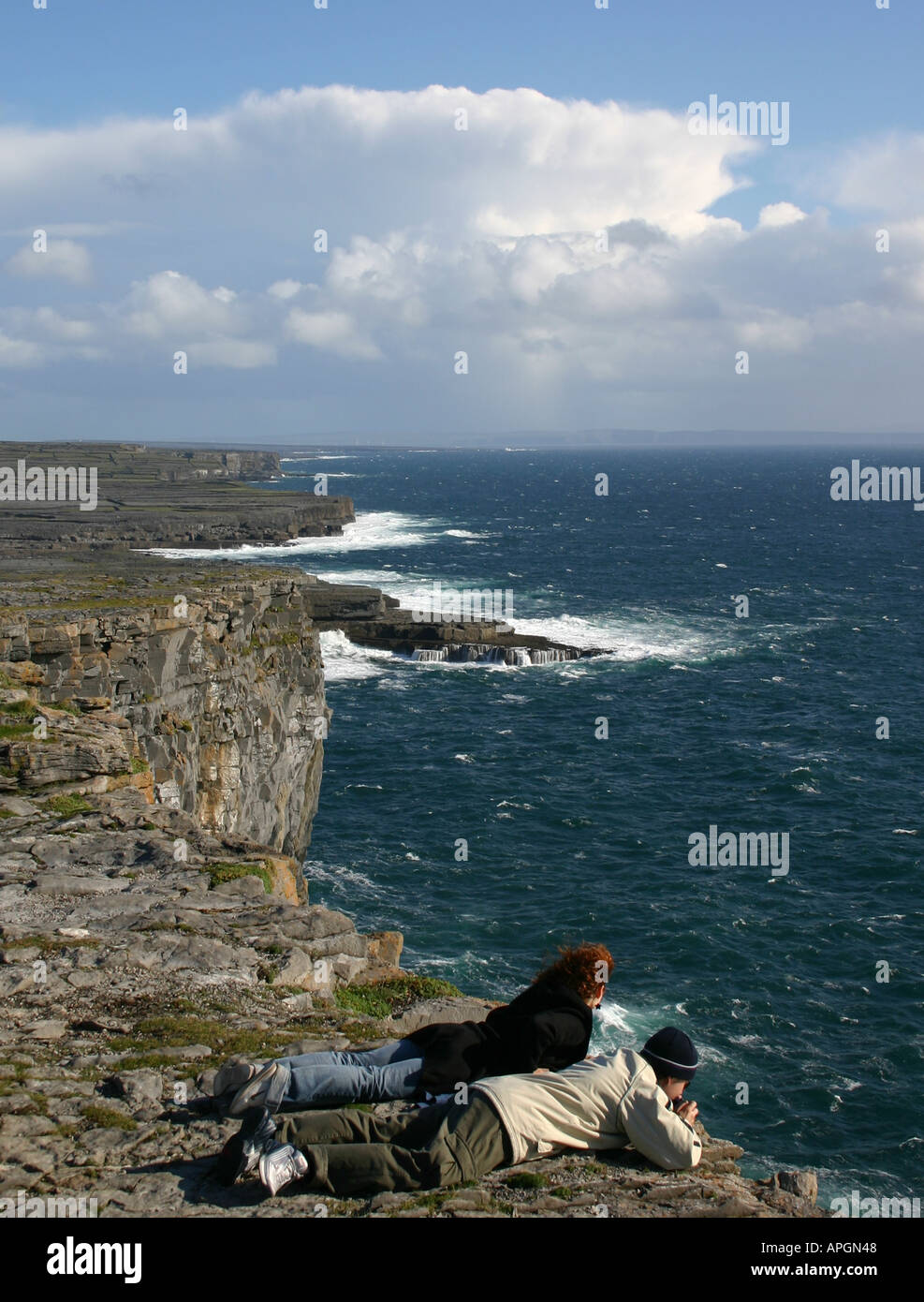 Tourists looking over the cliffs at Dun Aonghus fort, Inis Mor the Aran ...