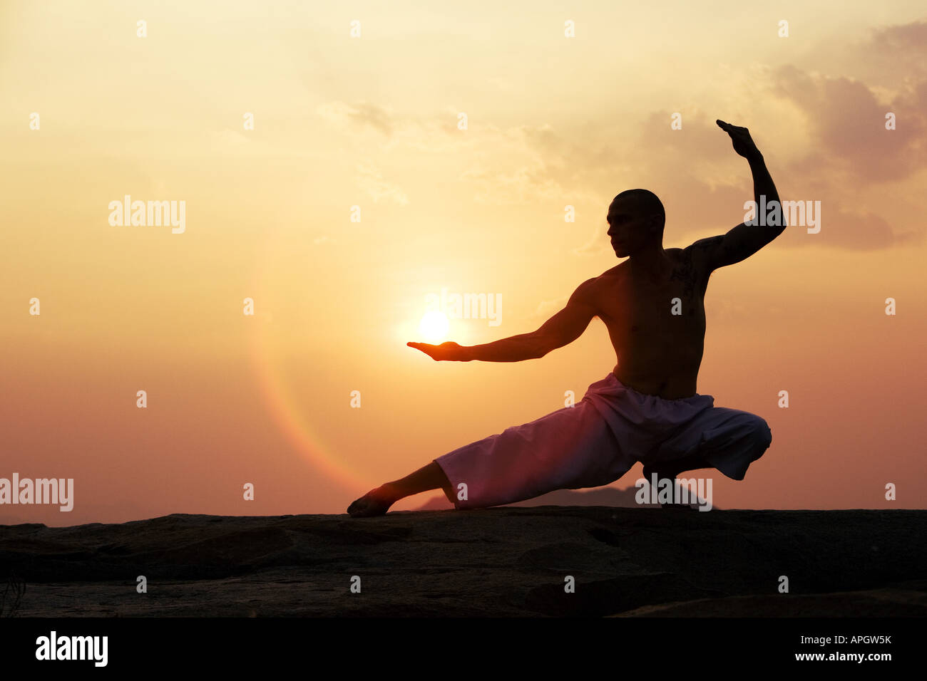 Man performing tai chi against a setting sun in india Stock Photo - Alamy