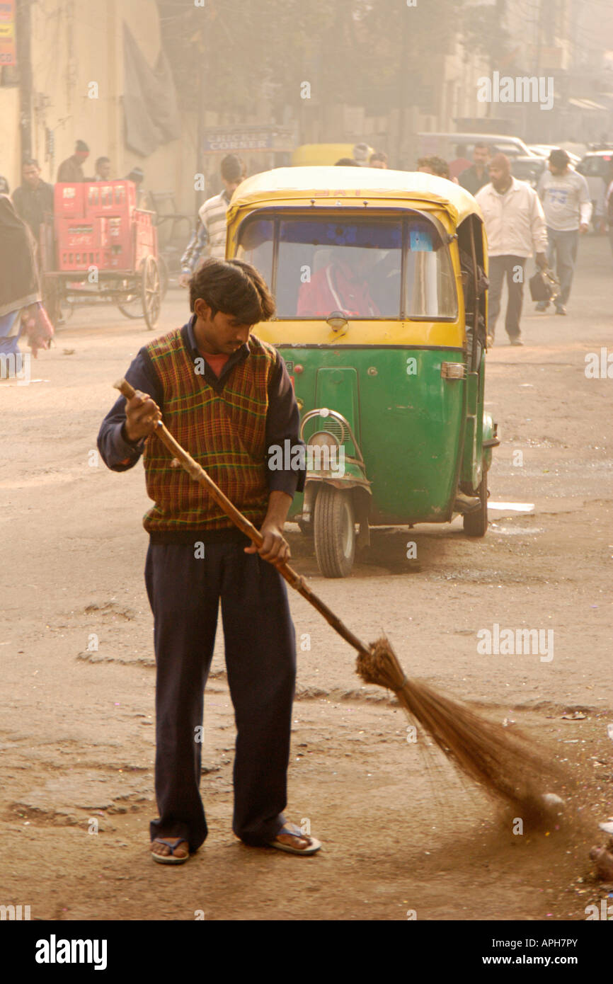 Man sweeping street with auto rickshaw in background, New Delhi, India ...