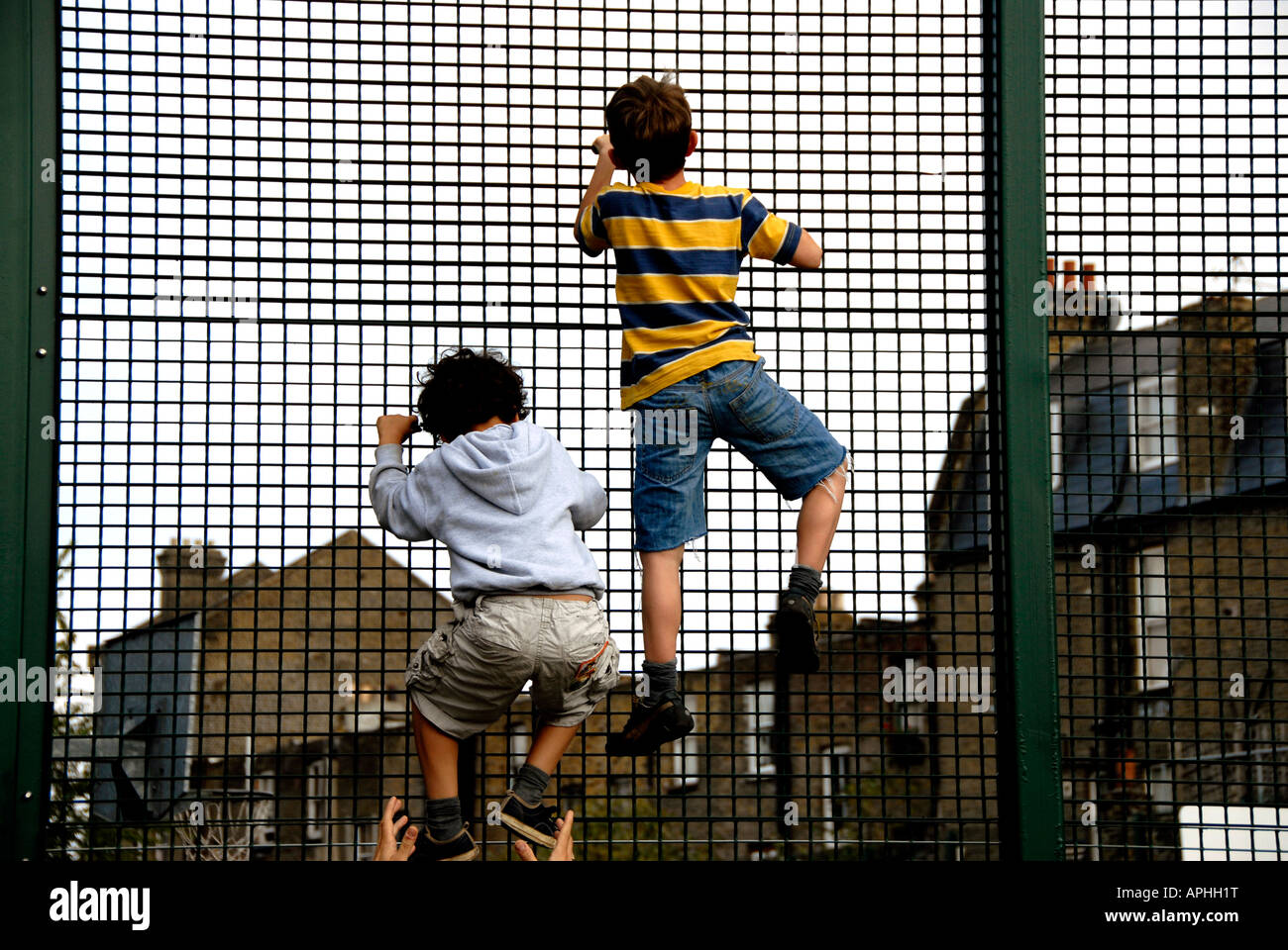 Young children climbing wire fence Stock Photo - Alamy