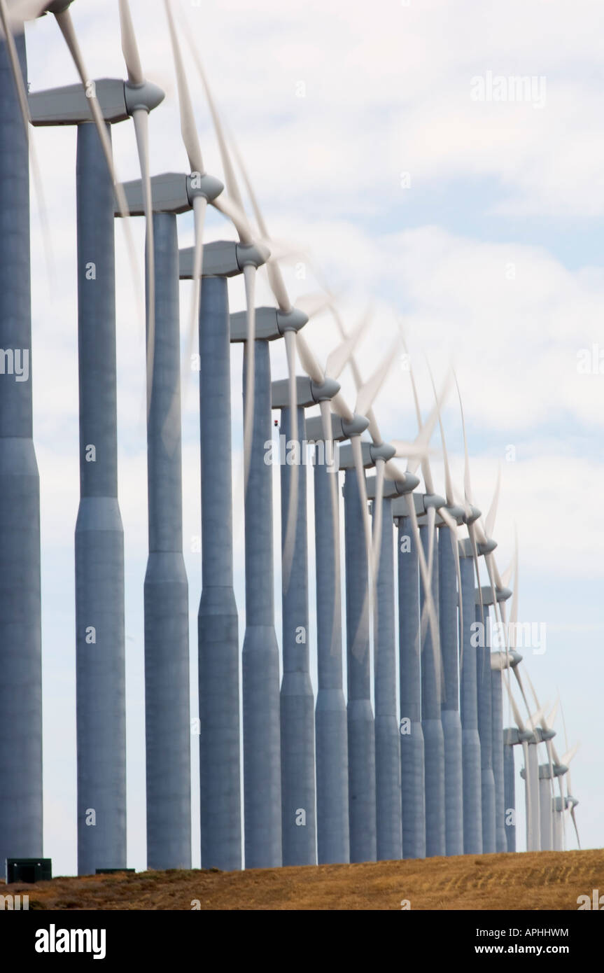 The propellers of a line of wind turbines spin in the wind as they ...
