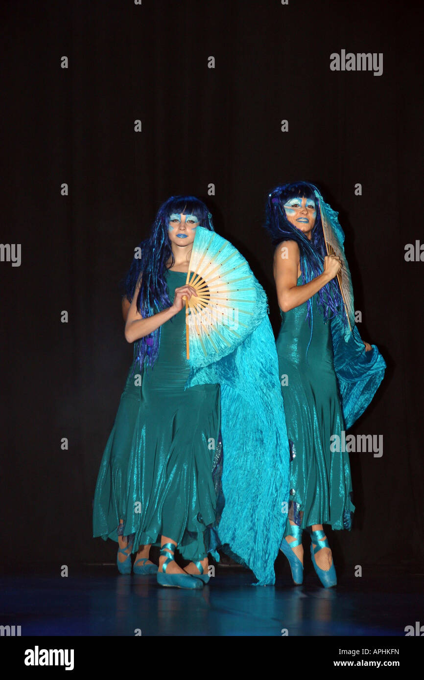 Ballet dancers with long blue hair and fans dance across the stage ...