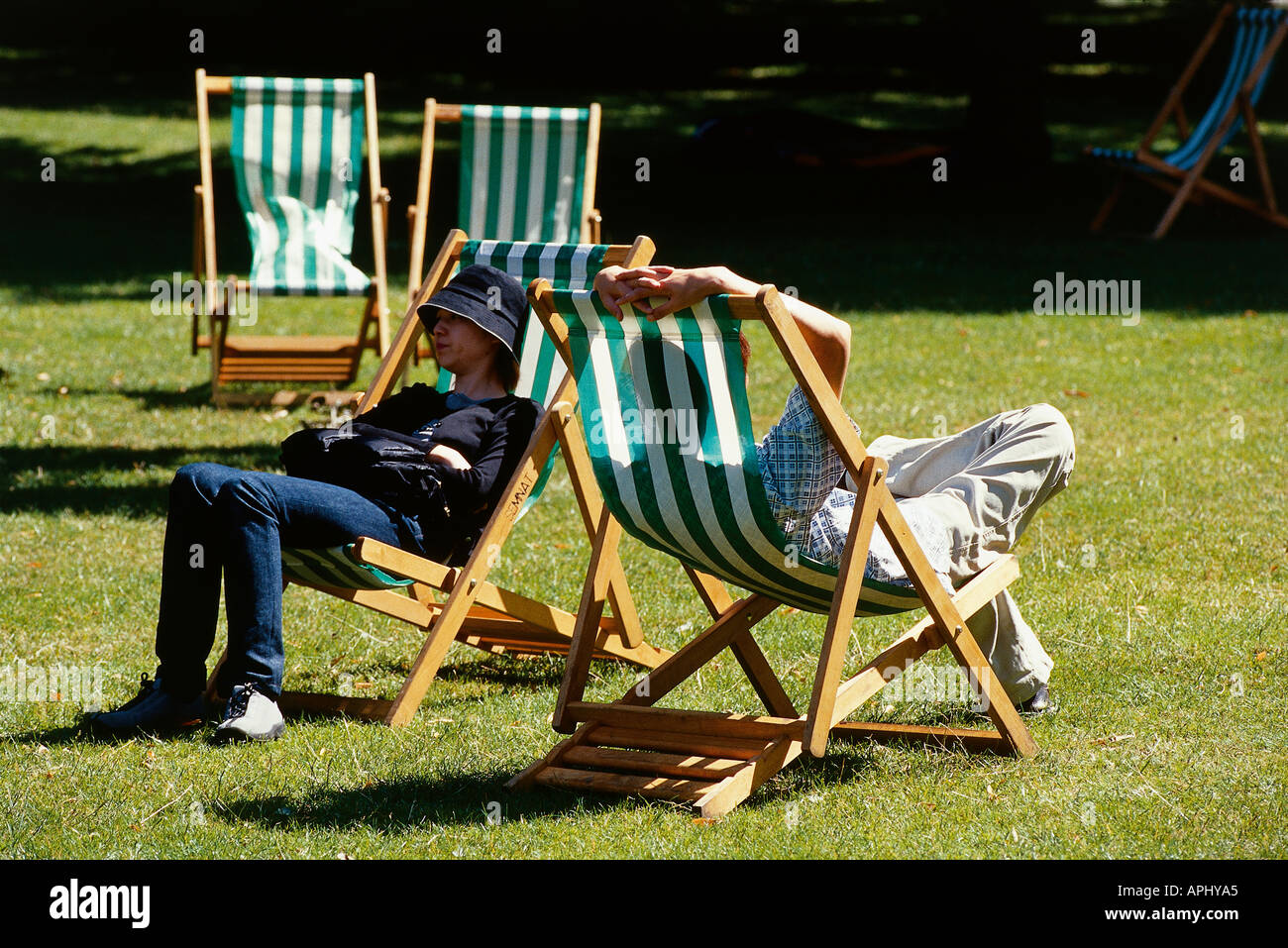Two people relaxing on deck chairs enjoying the sunshine in Kensington ...