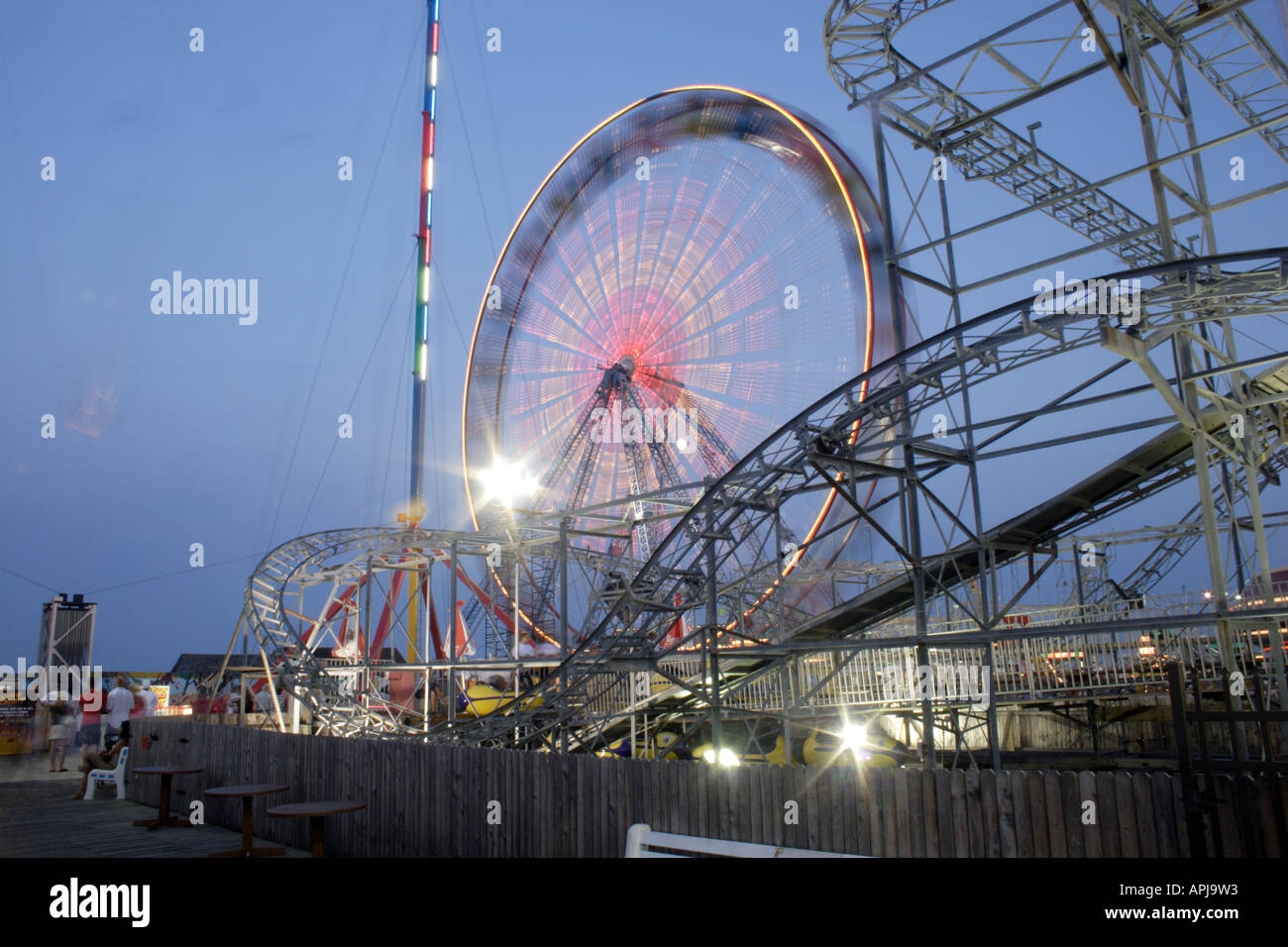 Summer evening fair grounds with ferris wheel and rides Stock Photo - Alamy