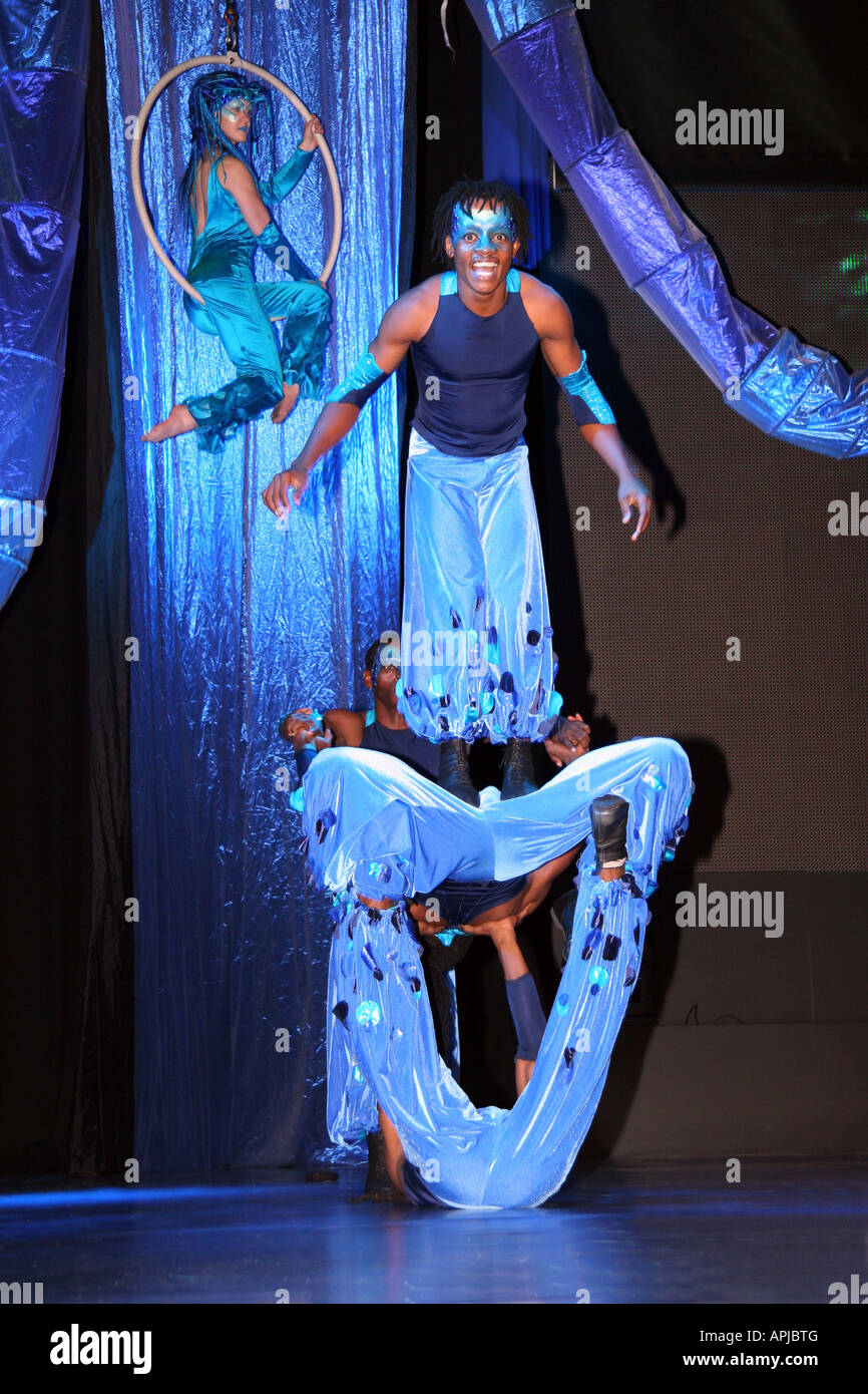 Acrobat standing on two others whilst another balances on a hoop in the ...