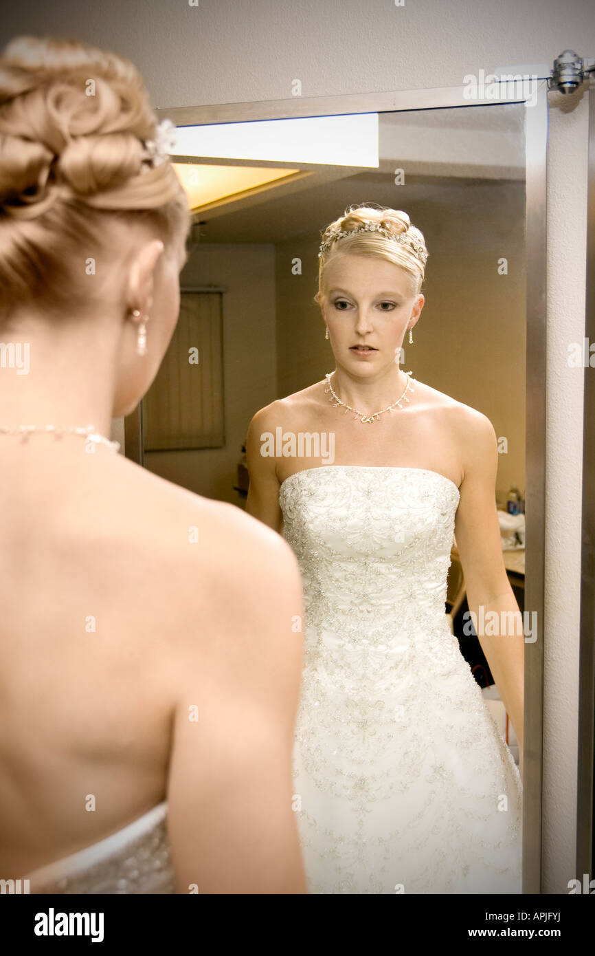 Bride looking into mirror on wedding day Stock Photo - Alamy