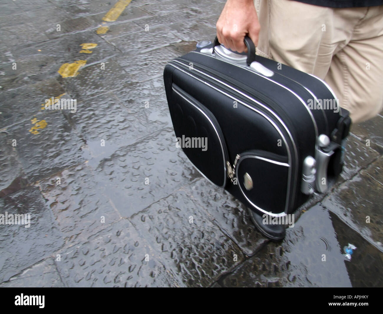 man carrying trolley case in street road in city town Stock Photo - Alamy
