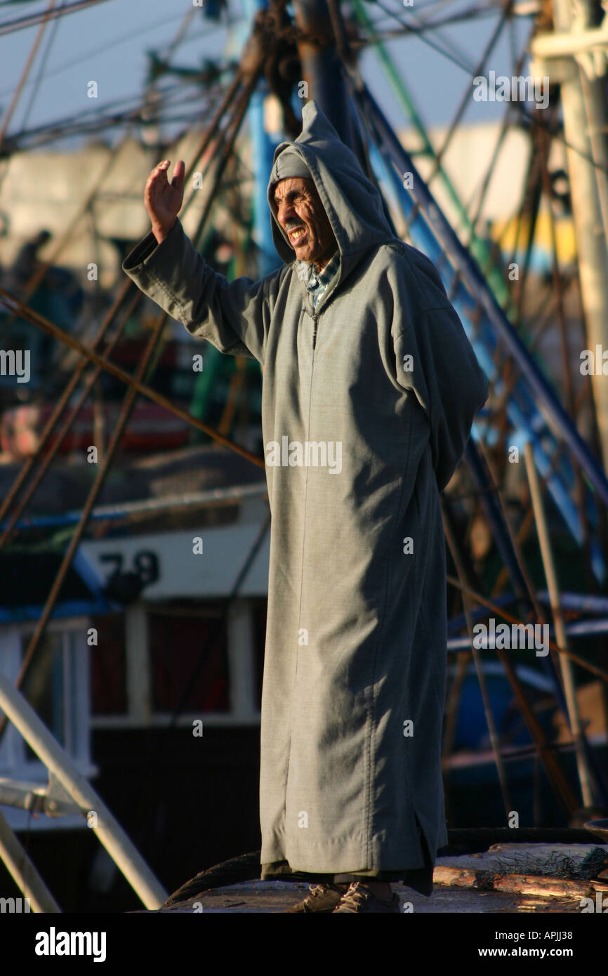 Fisherman in traditional clothing, so called chilaba, watching boats ...