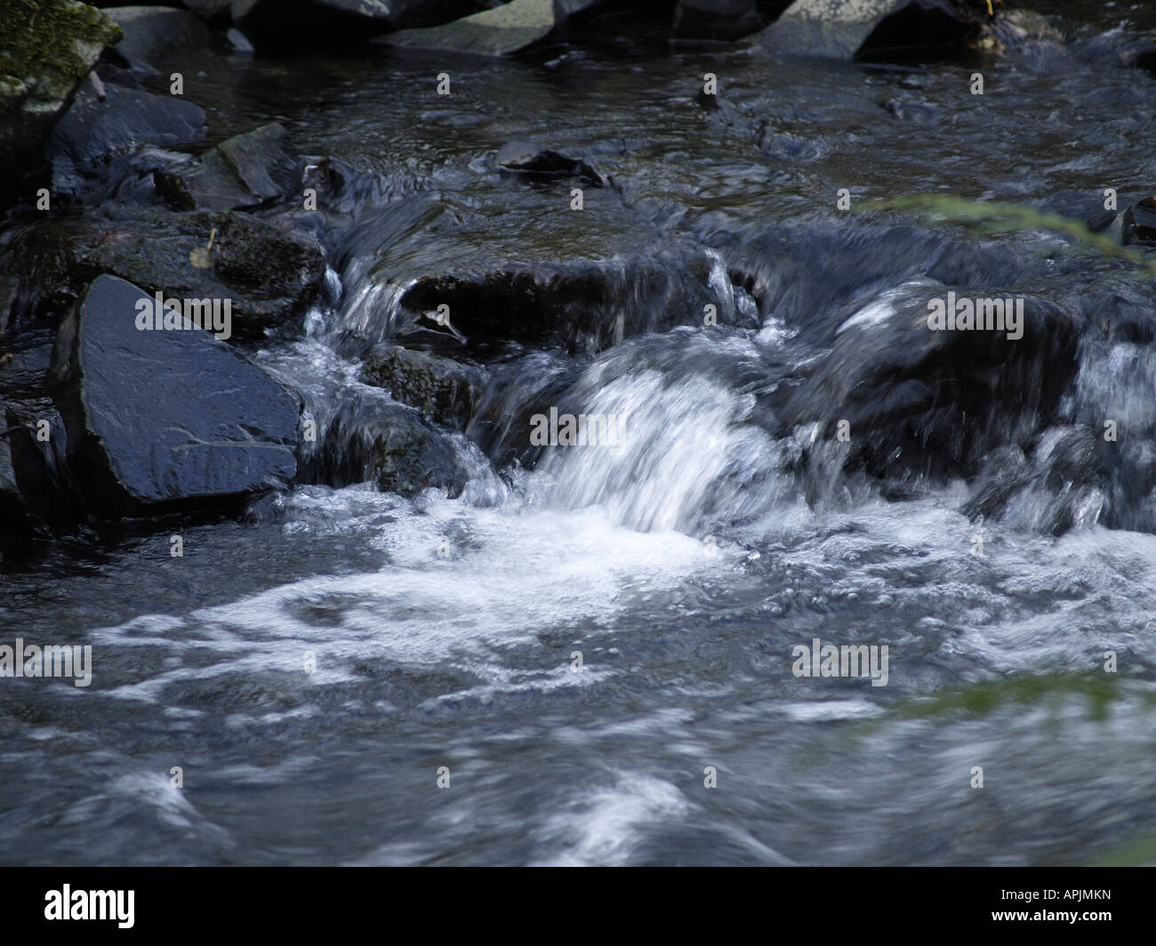 Small stream running over smooth rocks forming a small waterfall Stock ...