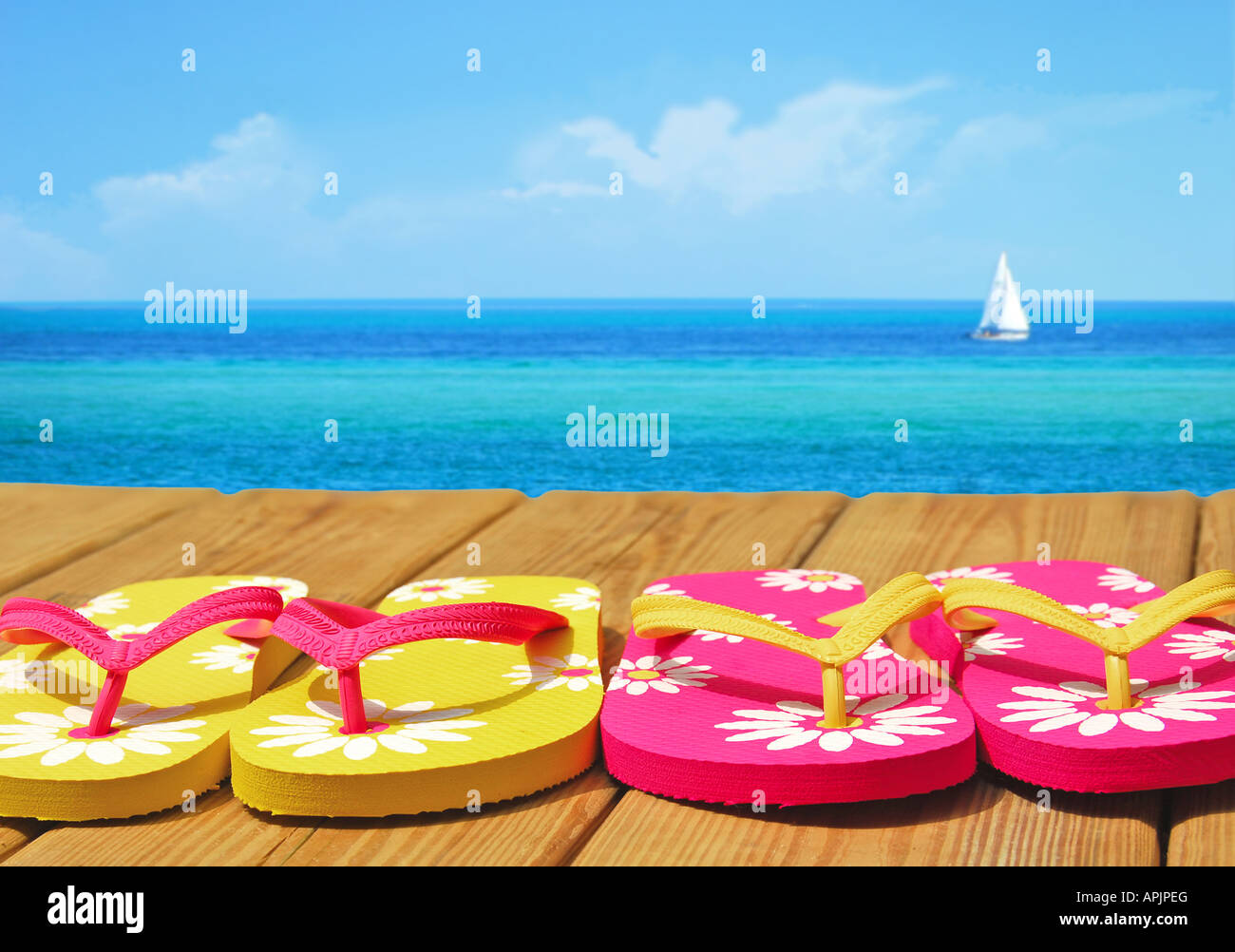 Colorful sandals on dock by ocean with sailboat in distance Stock Photo ...