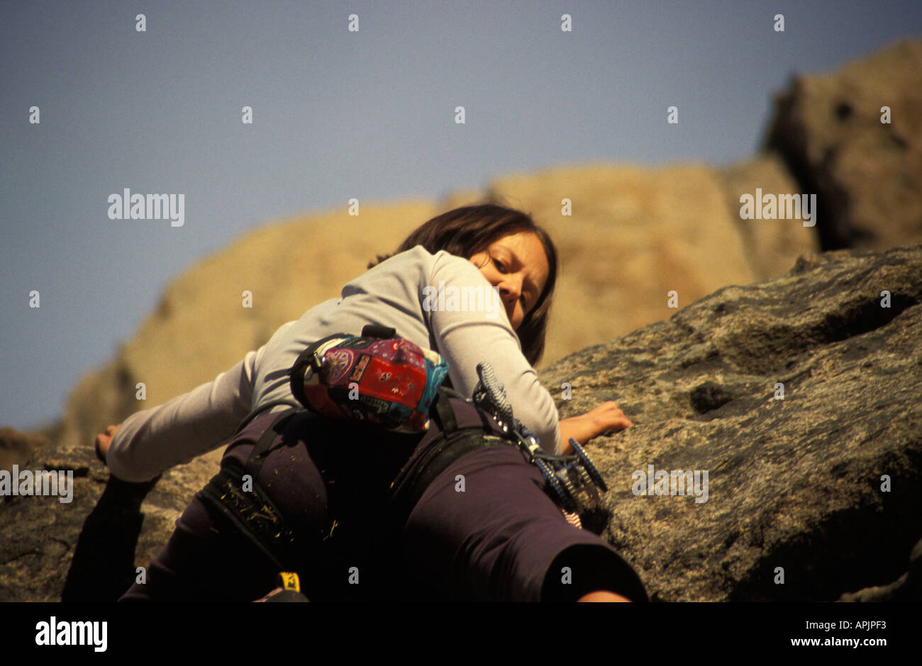 Idaho City of Rocks female climber looks back while climbing Stock ...