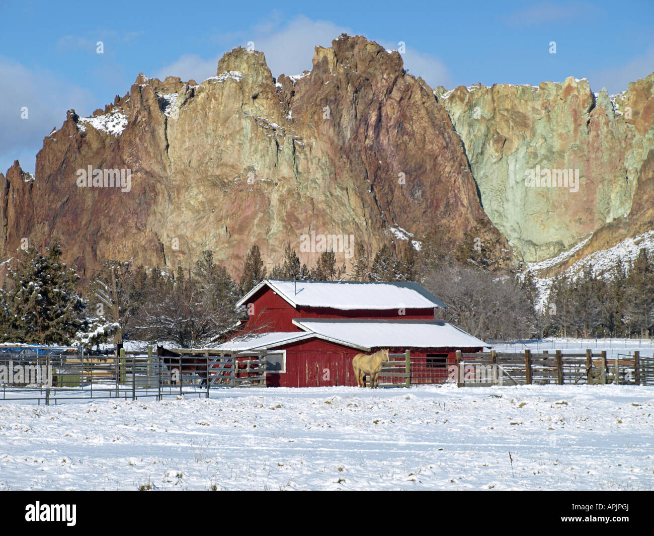 A red barn on a small farm below the sheer cliffs of Smith Rock with a ...