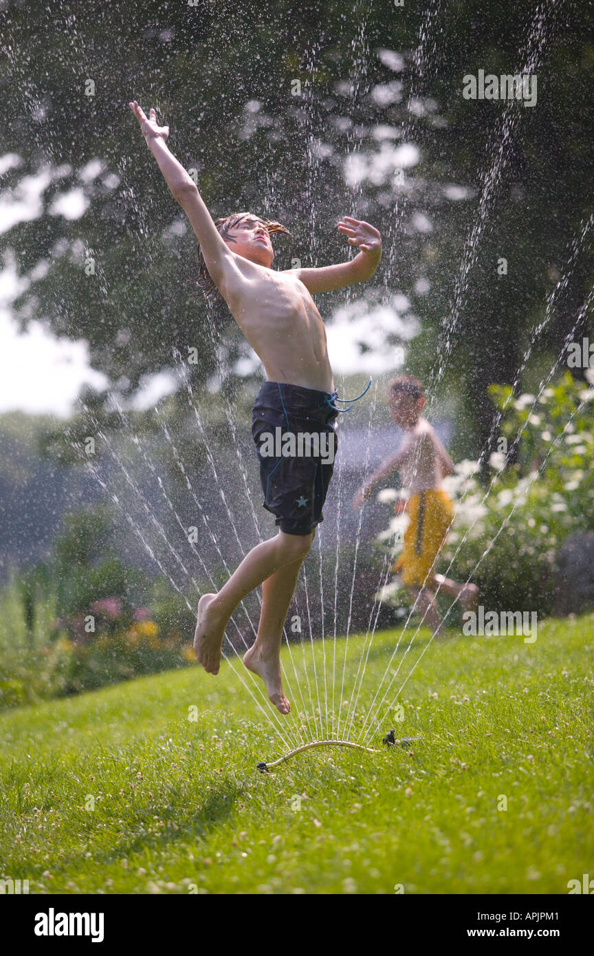 Two kids playing water sprinkler hi-res stock photography and images ...
