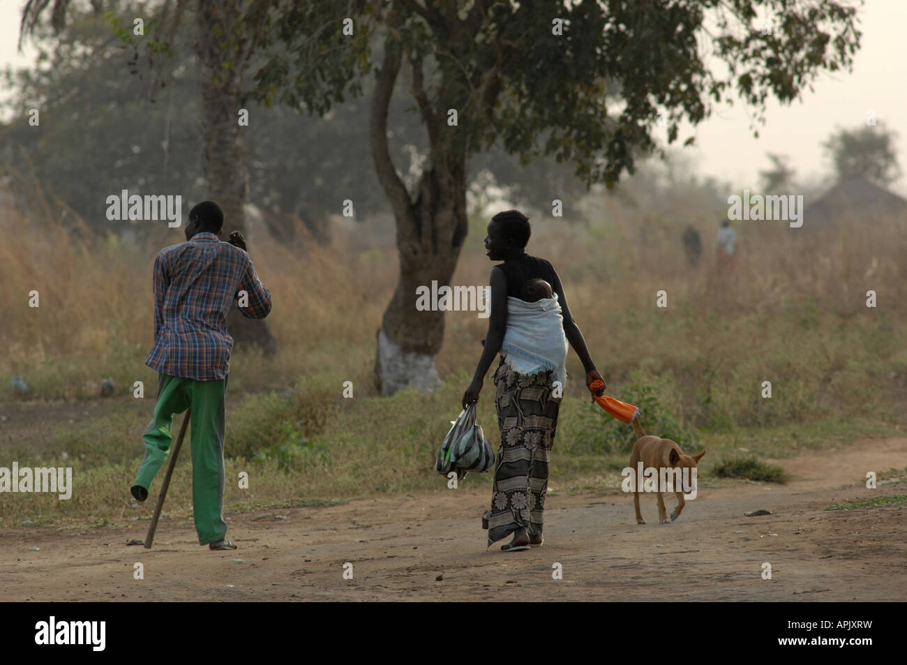 An African man with one leg talking to a woman with child in an African ...