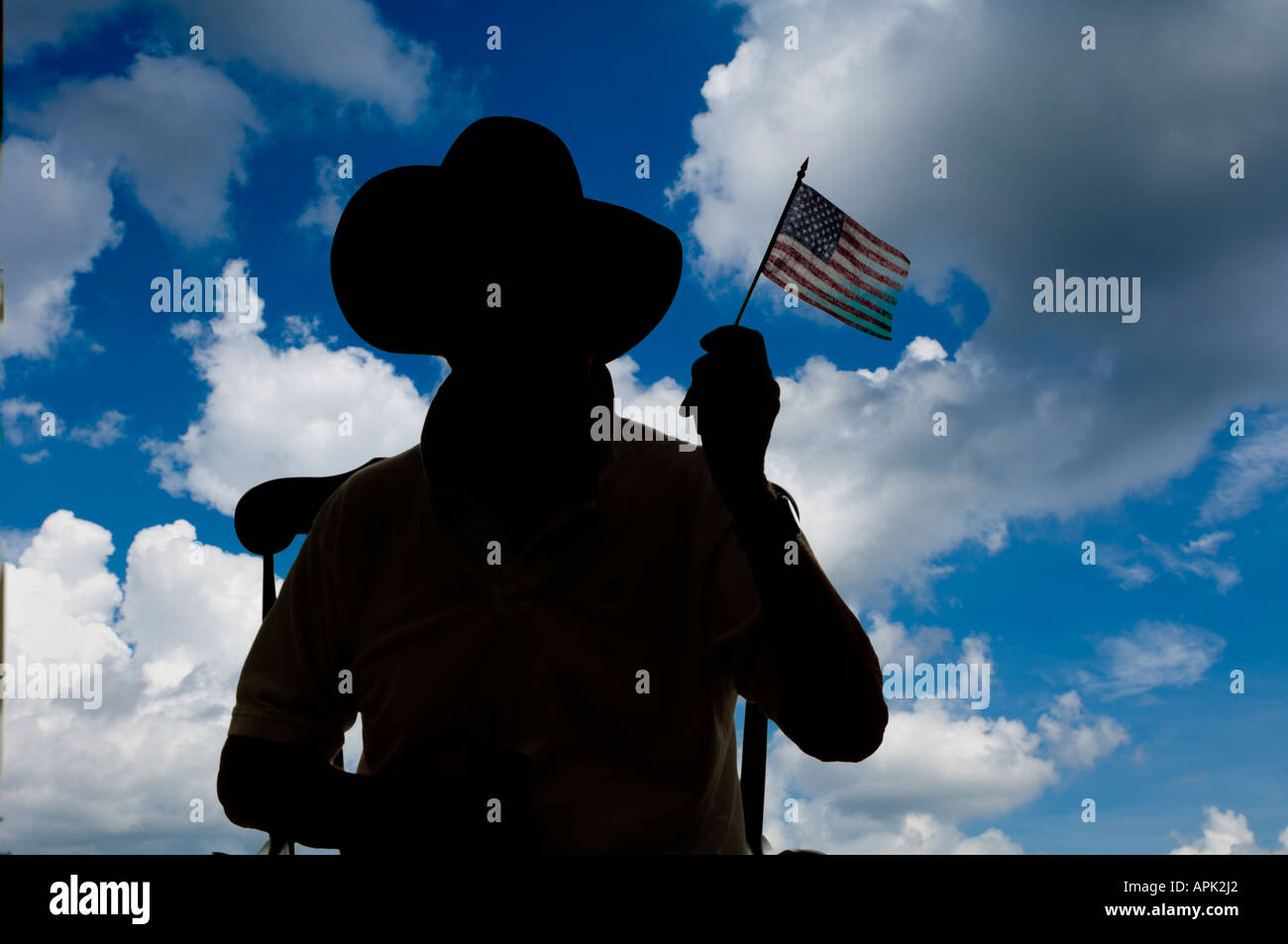 silhouette of man sitting in rocking chair holding small American flag ...