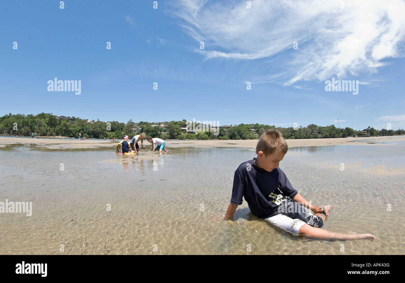 a boy sits by himself left out of the fun at the beach Stock Photo - Alamy