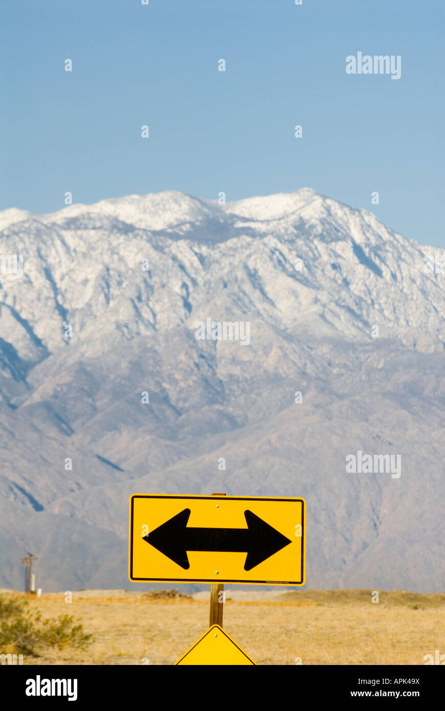 Sign highway direction peak mountain snow covered desert yellow arrow ...