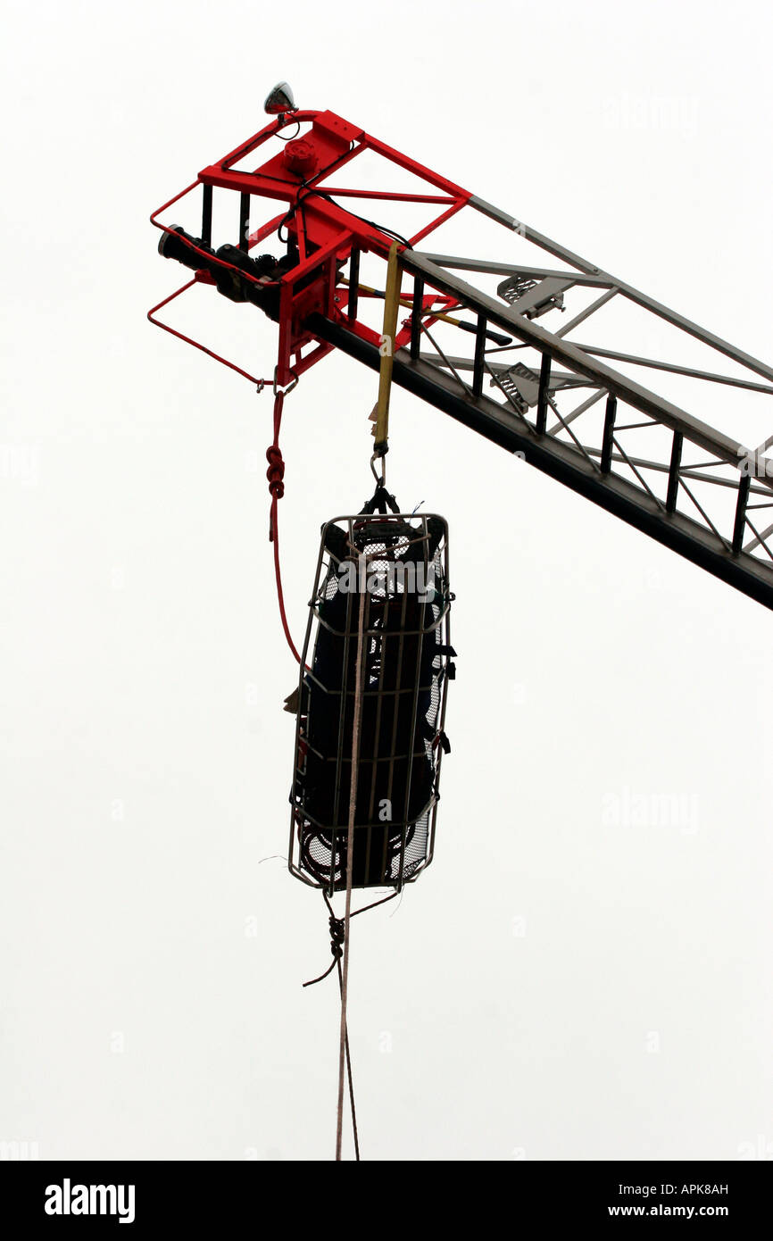 A high aerial rescue basket with a victim hanging from the ladder ...