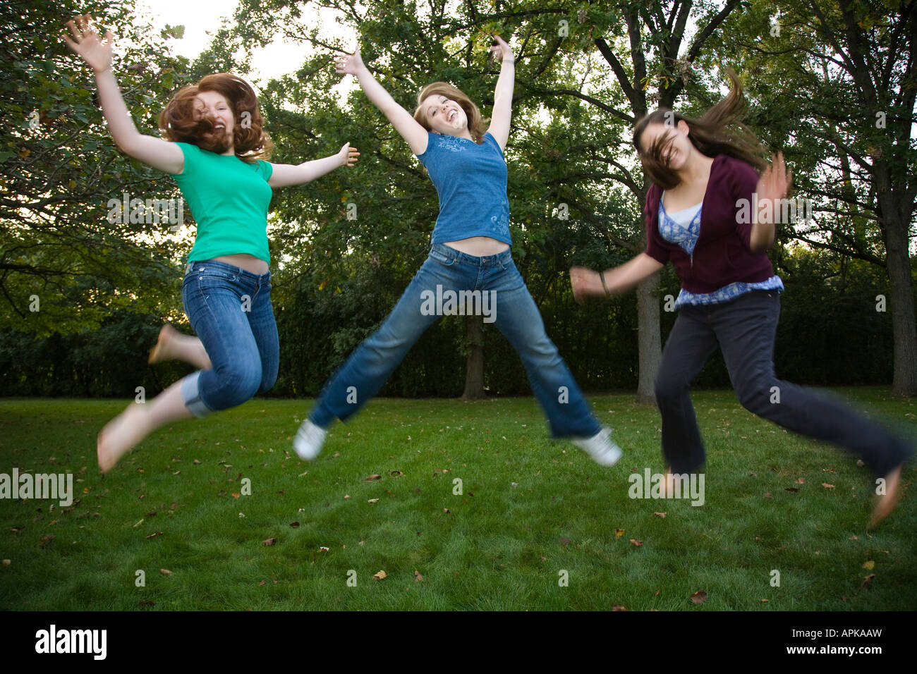 ILLINOIS Riverwoods Three teenage girls jumping in mid ait in backyard ...