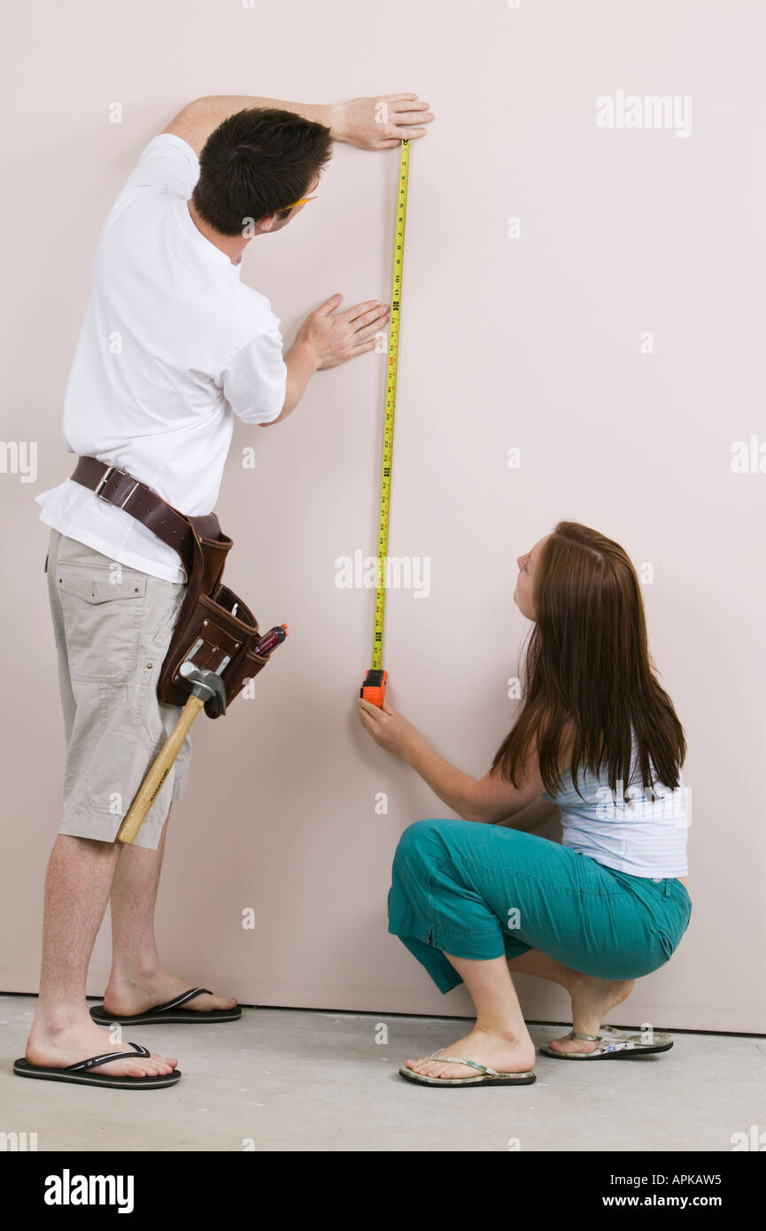 Couple Measuring a Wall Stock Photo - Alamy
