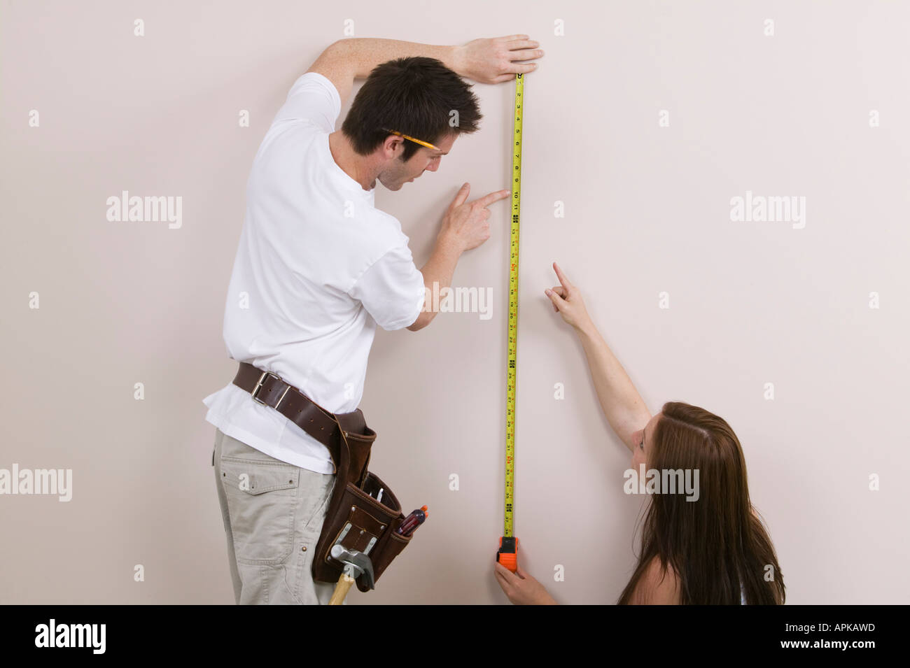 Couple Measuring a Wall Stock Photo - Alamy