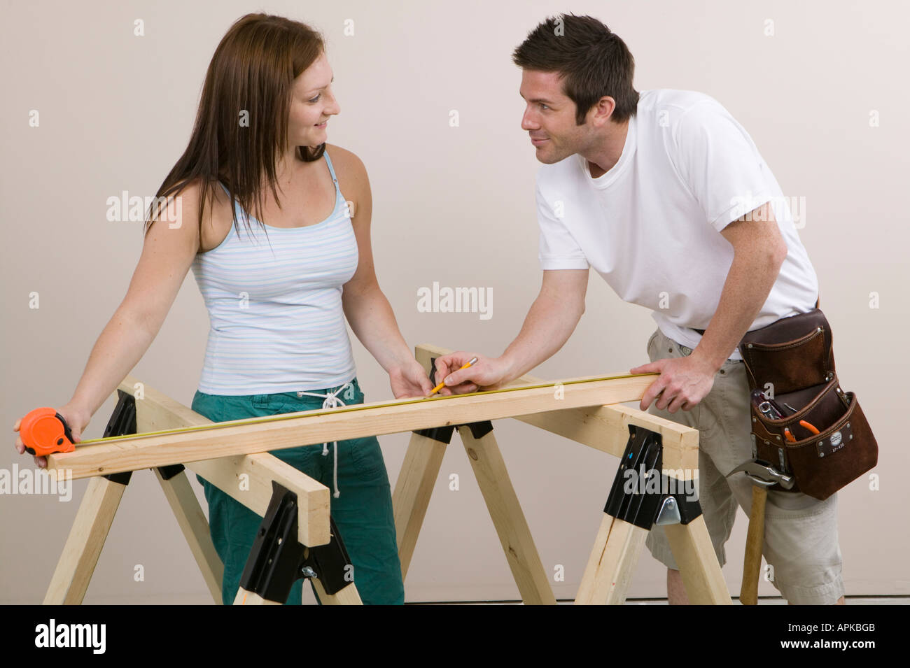 Couple Measuring a Board Stock Photo - Alamy