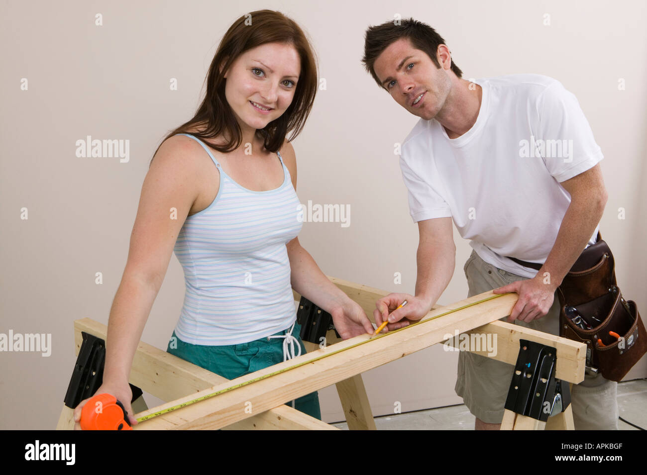 Couple Measuring a Board Stock Photo - Alamy