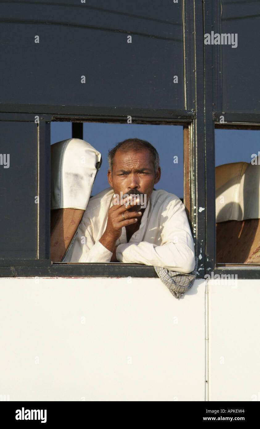 Man smoking a cigarette out a bus window, India Stock Photo - Alamy
