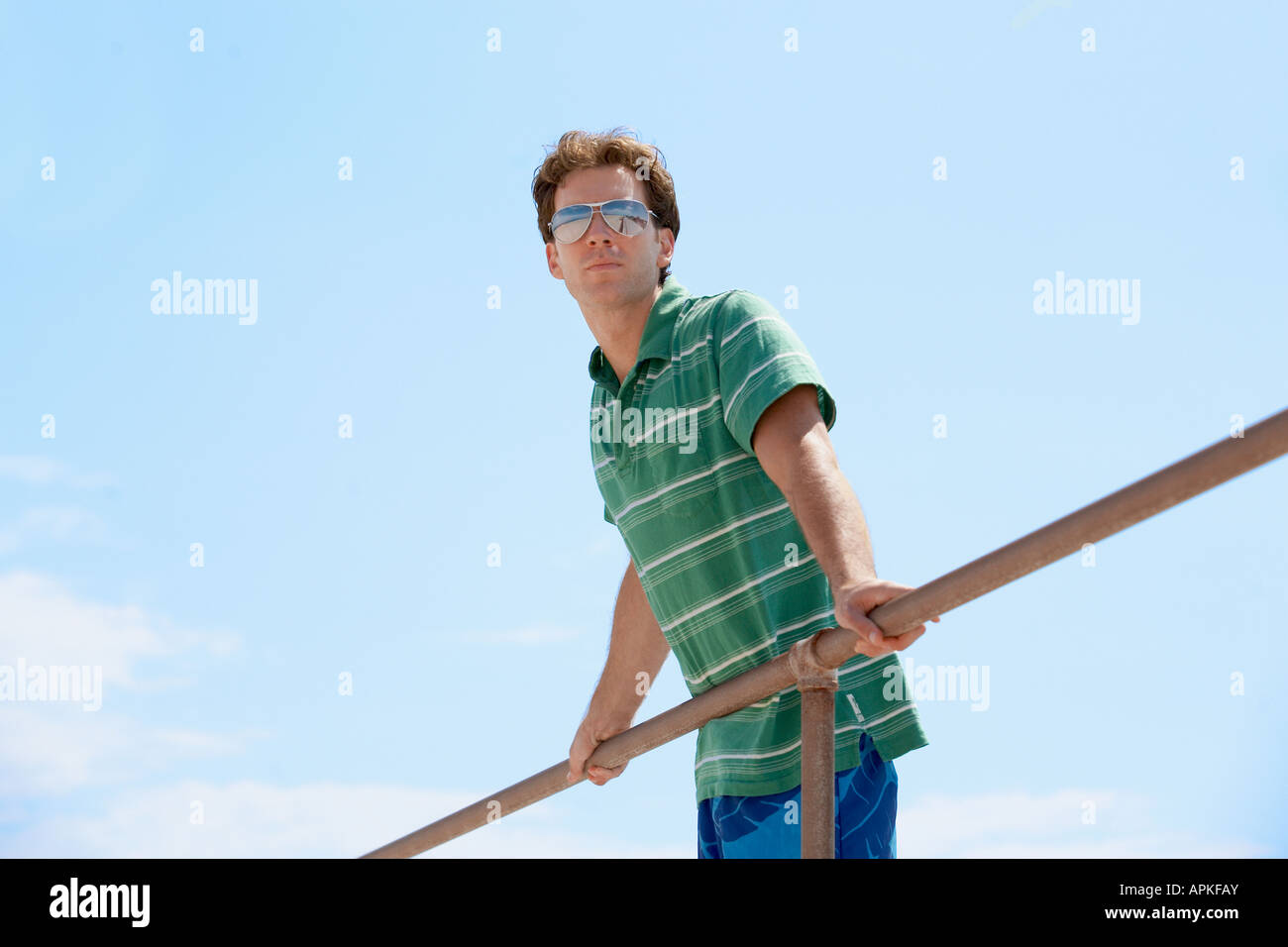 Young man leaning against railings (low angle view Stock Photo - Alamy