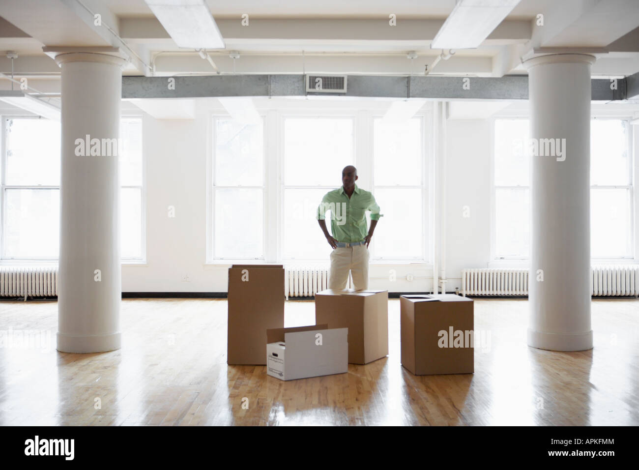 Man standing by cardboard boxes in empty office Stock Photo - Alamy
