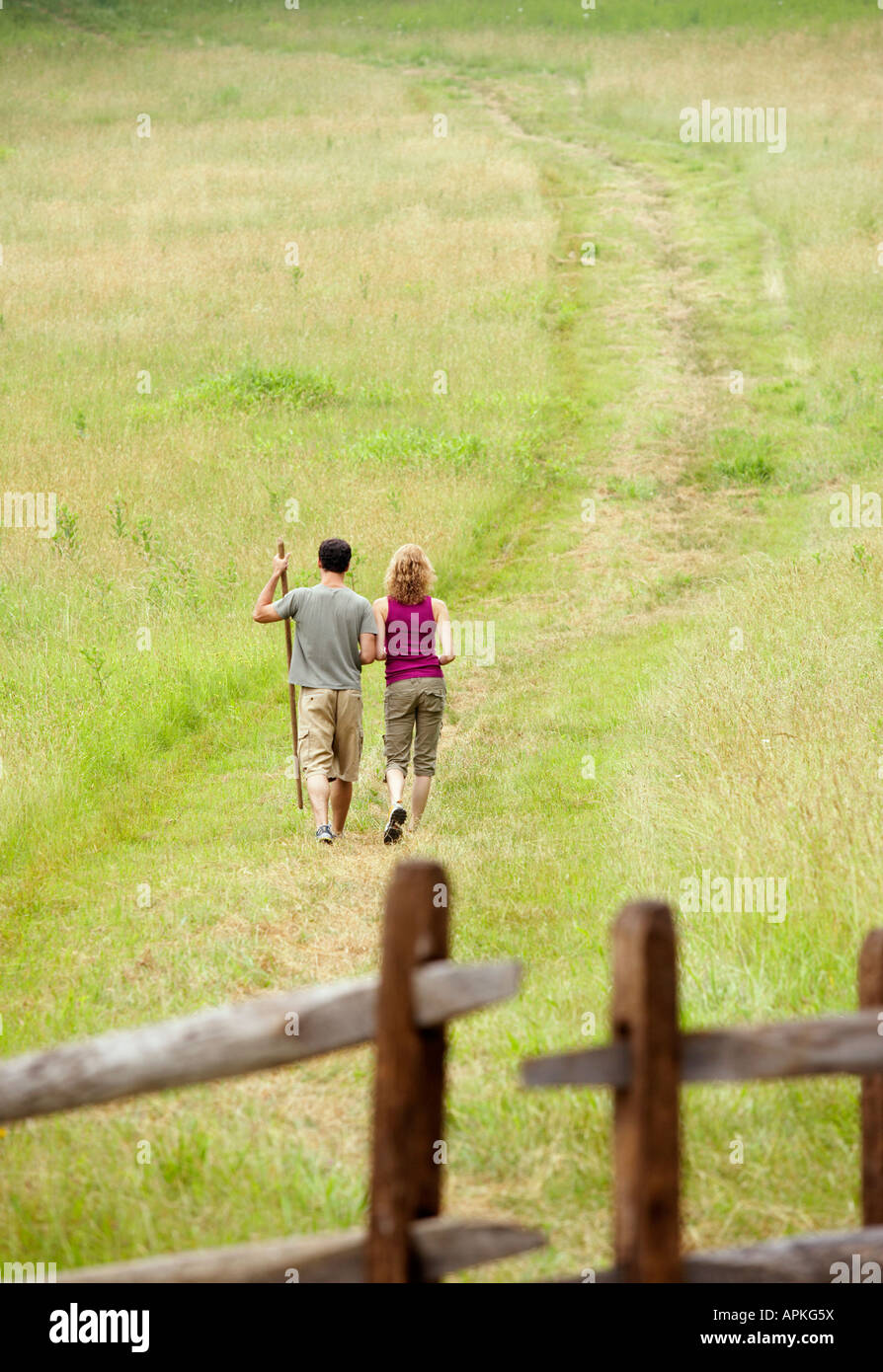 Couple walking in field near wooden gate Stock Photo - Alamy