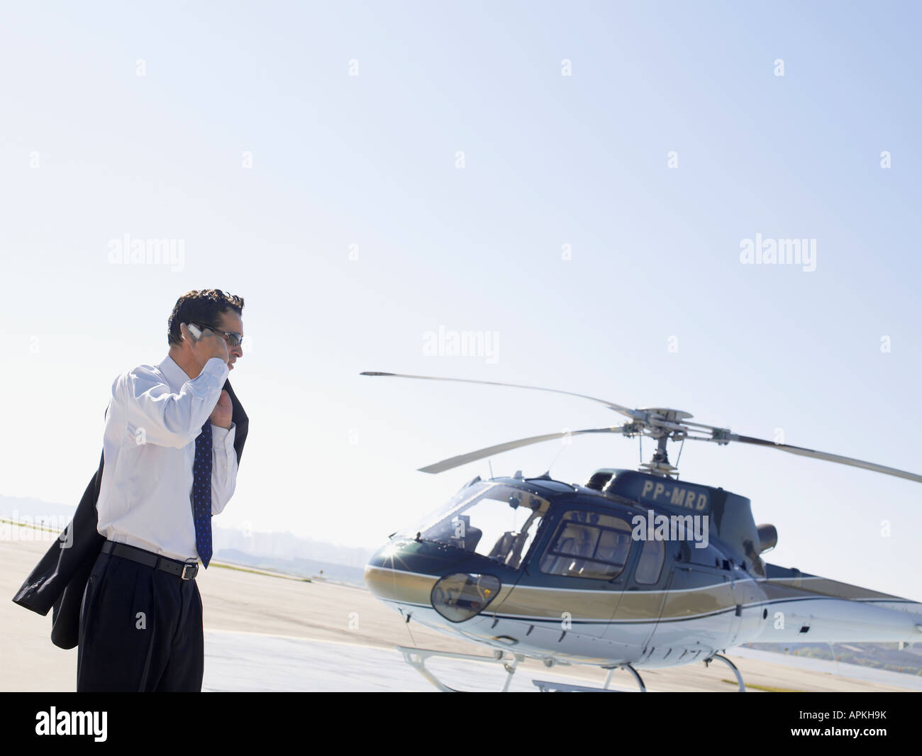 Businessman using cell phone near helicopter Stock Photo - Alamy