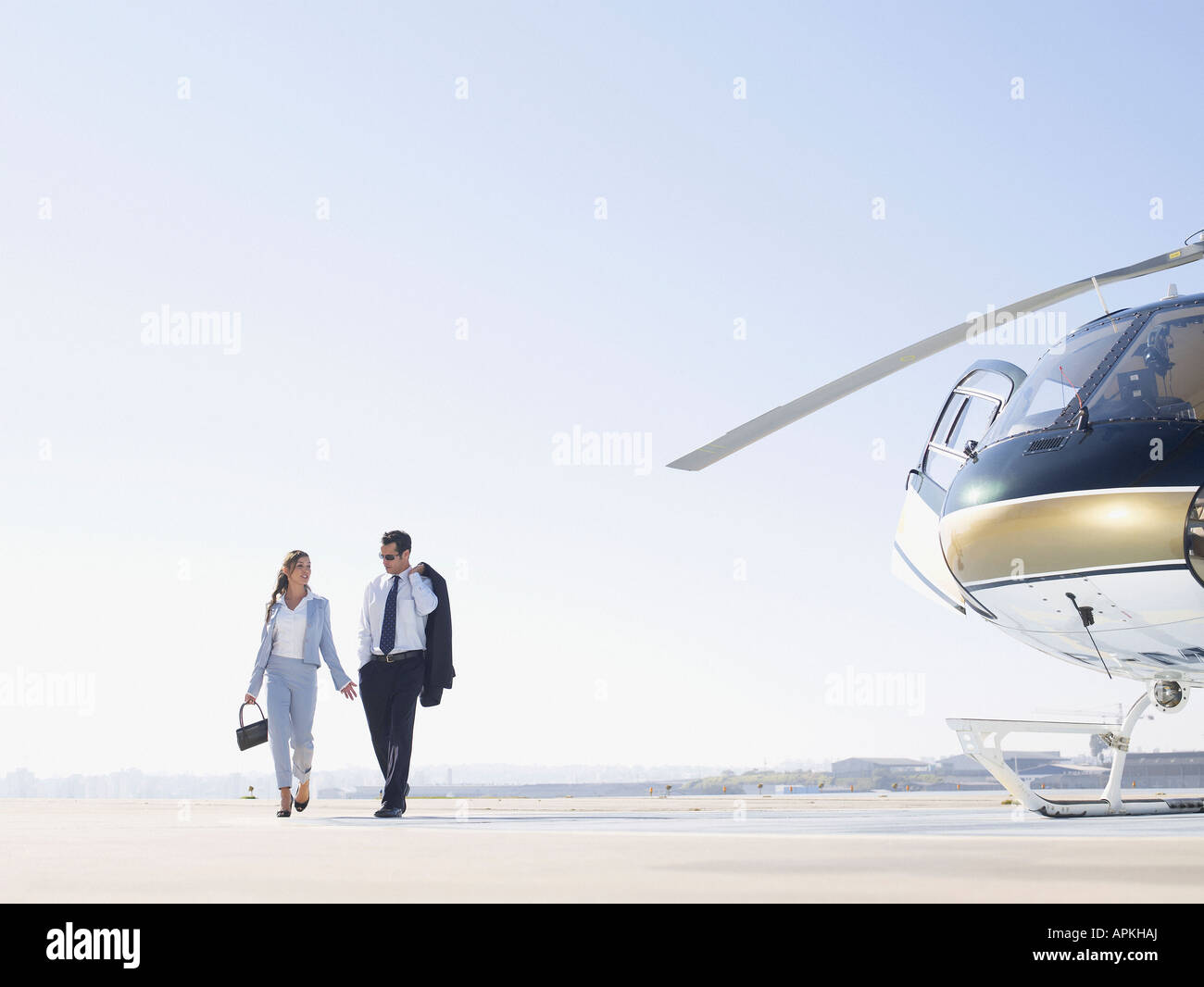 Two businesspeople walking on runway near helicopter Stock Photo - Alamy