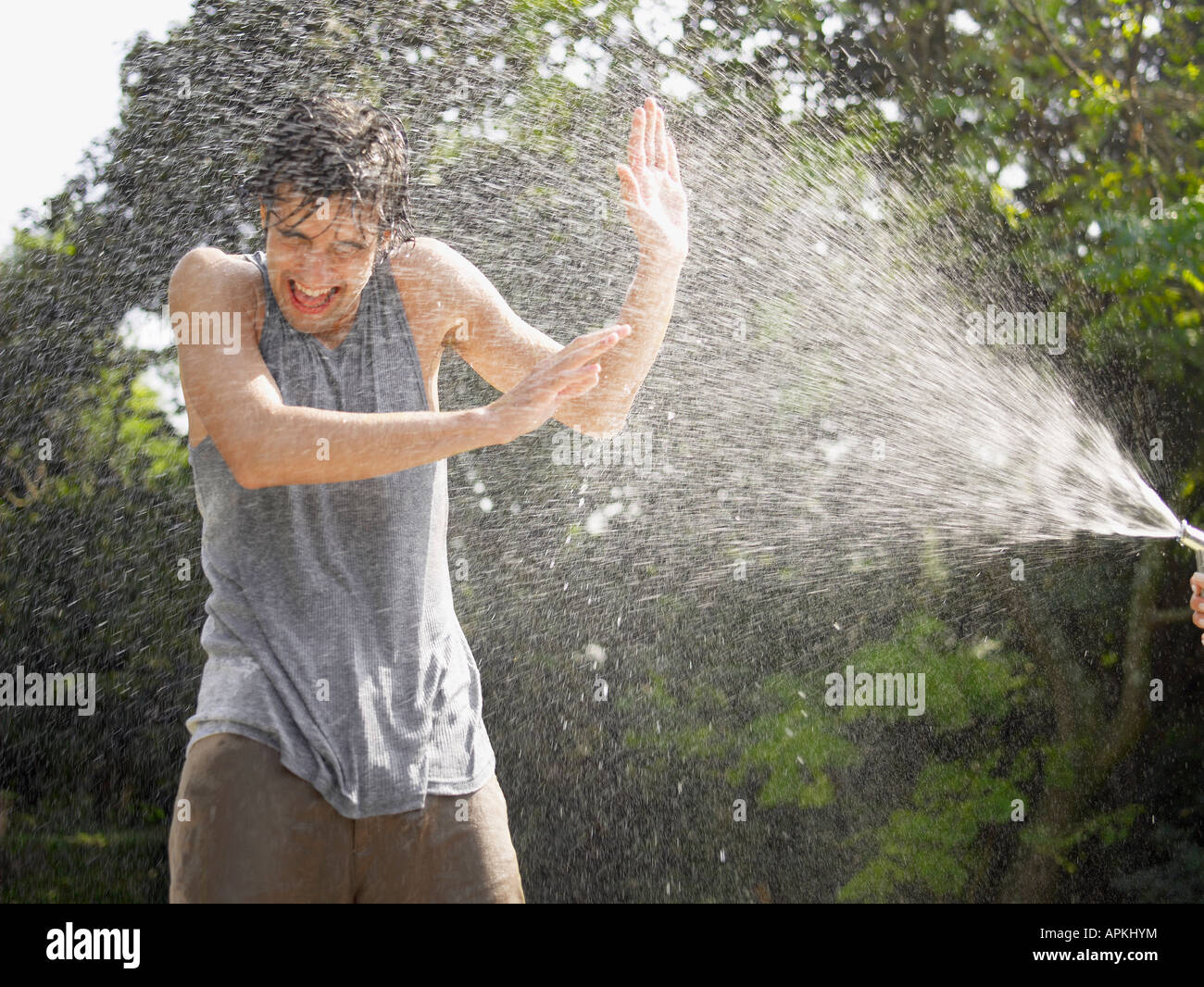 Young man under water spray Stock Photo - Alamy
