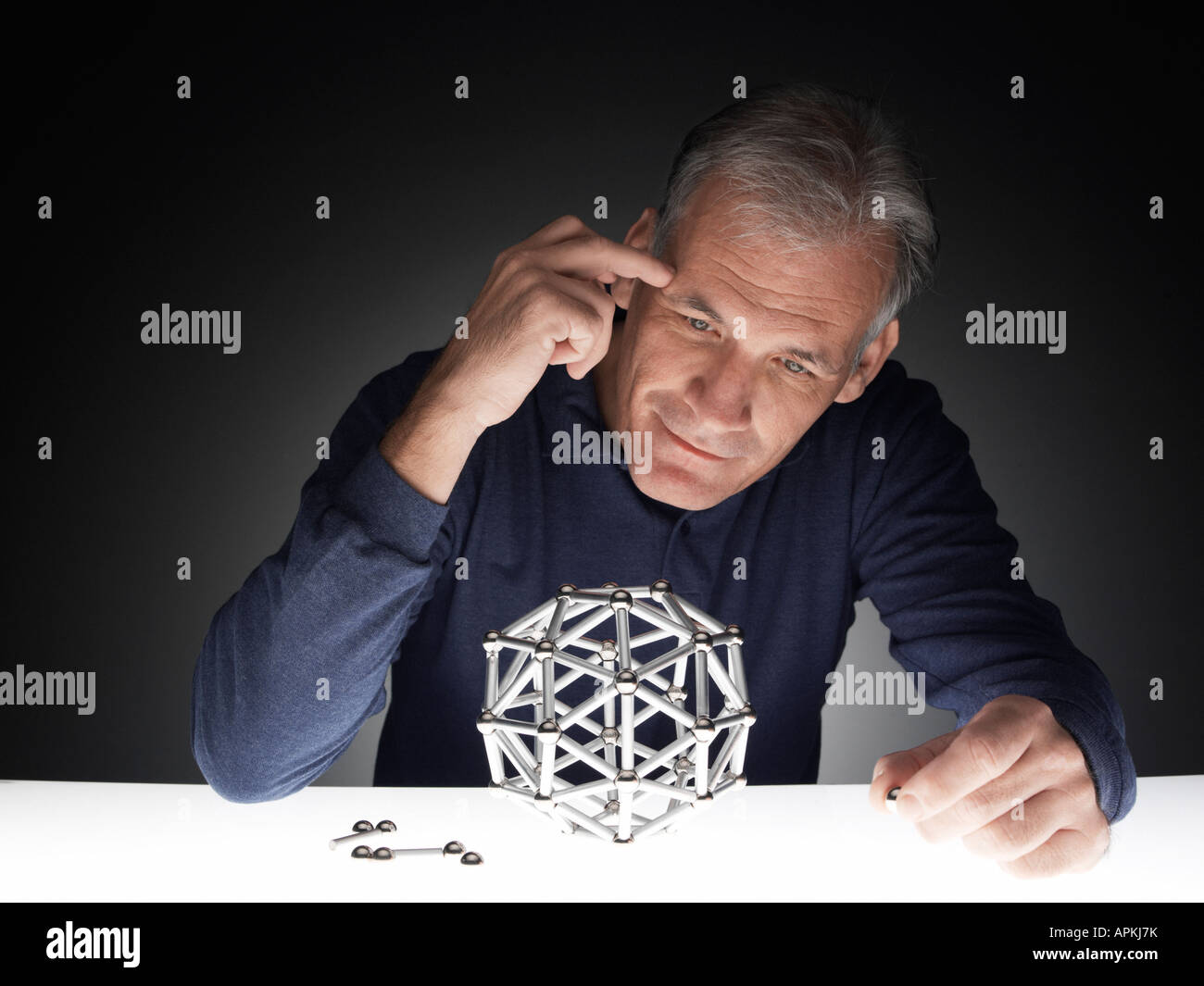 Mature man building polyhedron Stock Photo - Alamy