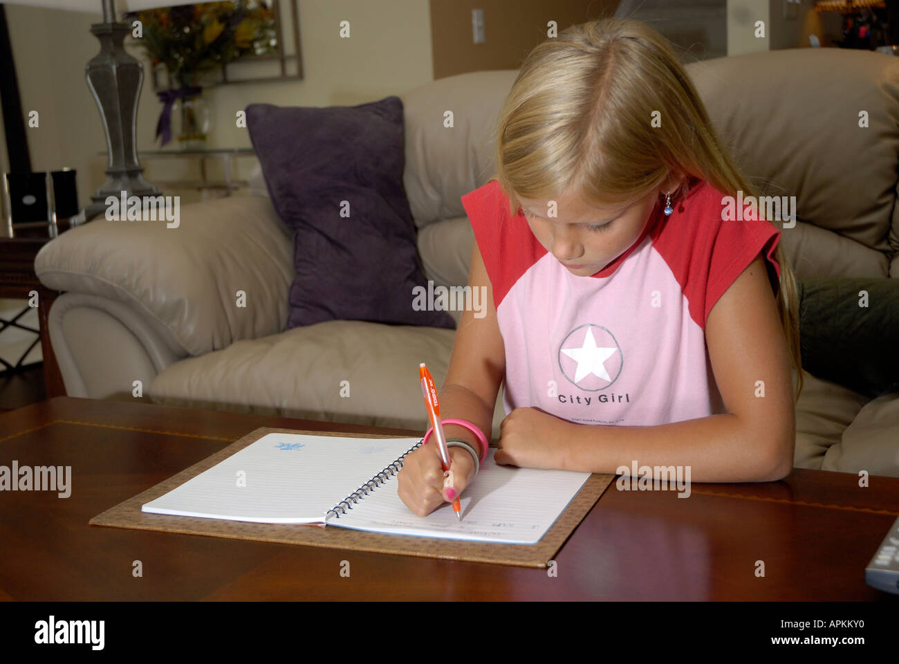 8 year old girl writes in her journal in the family living room Stock ...