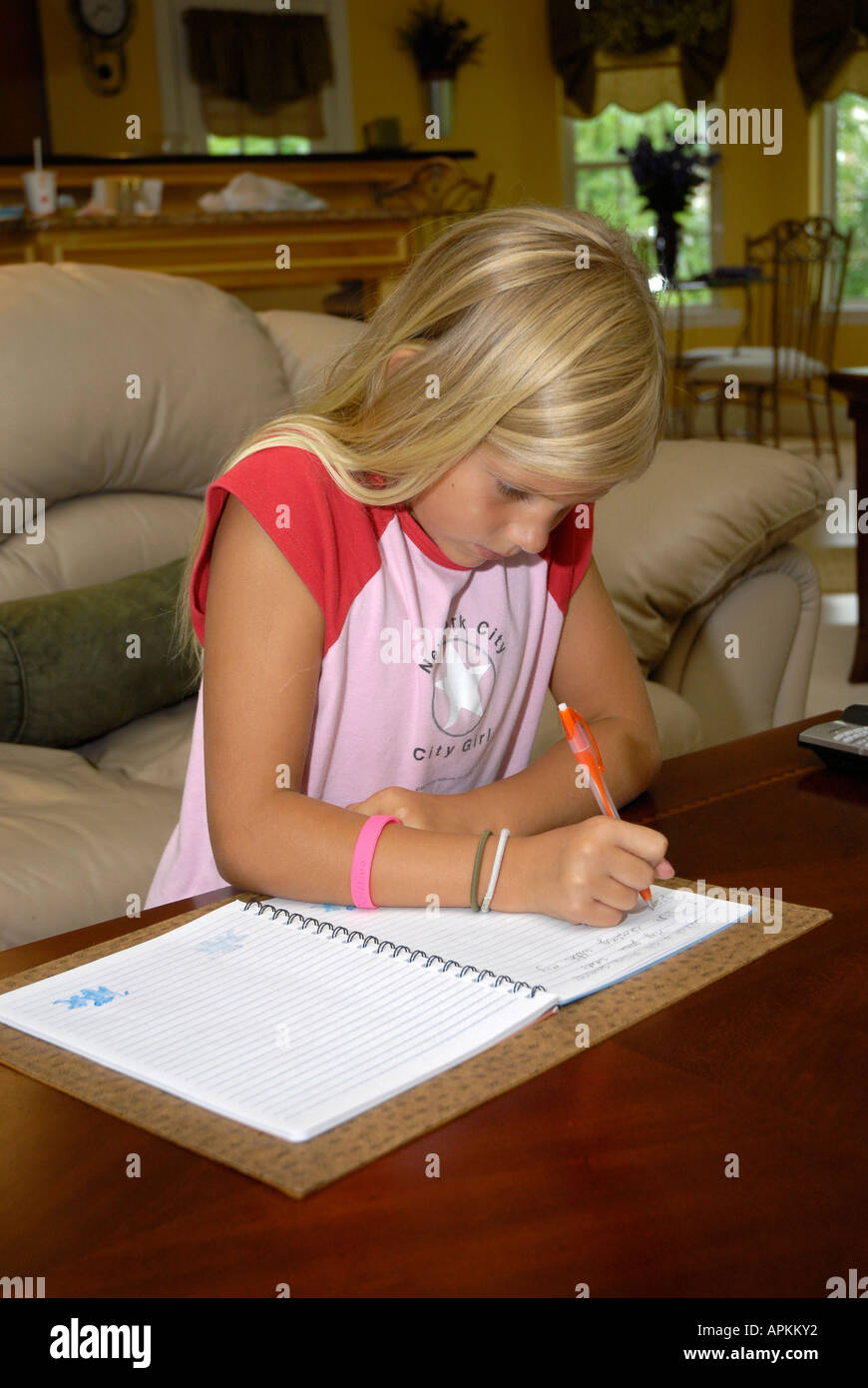 8 year old girl writes in her journal in the family living room Stock ...