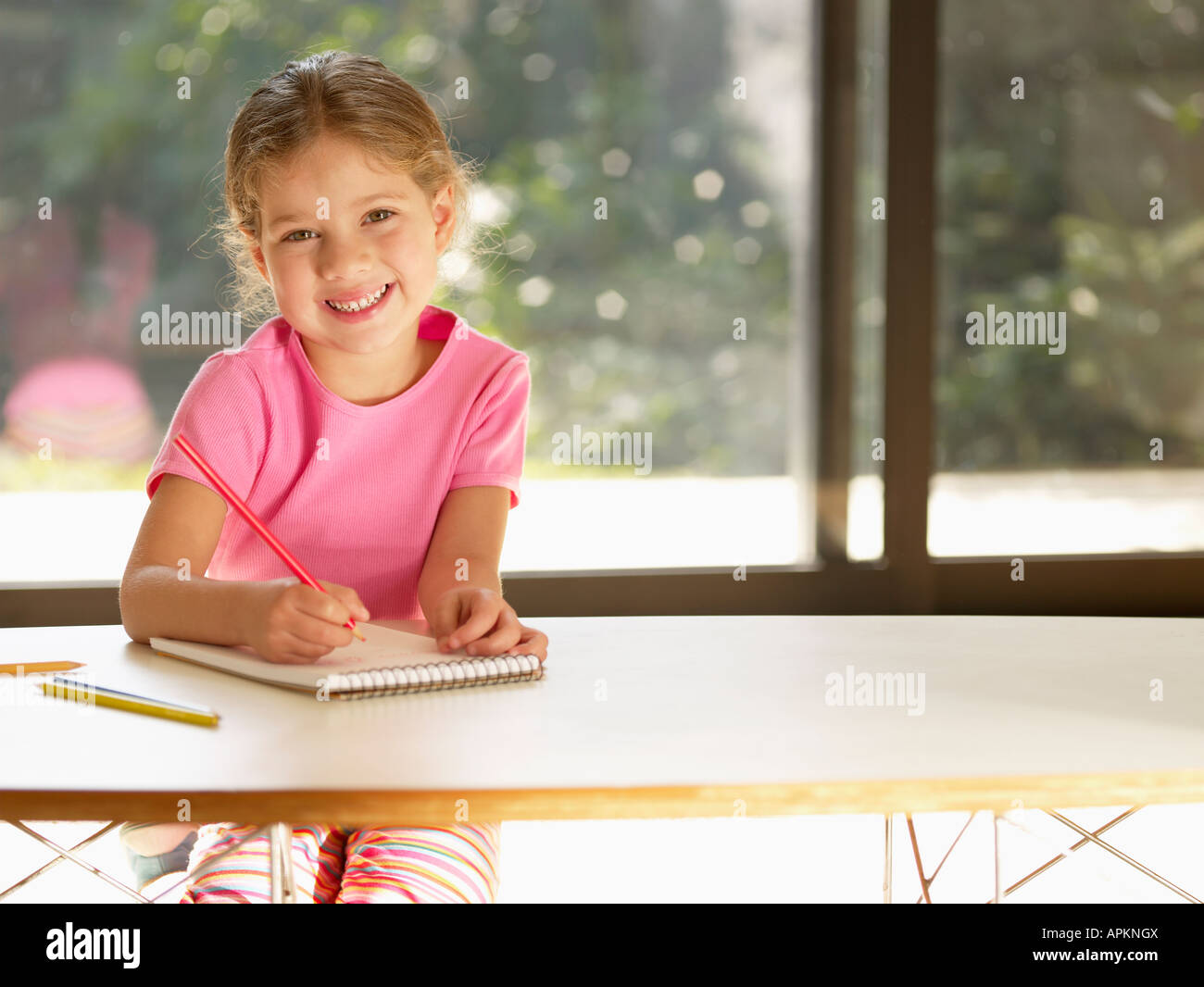 Girl writing with colored pencil on notepad (portrait Stock Photo - Alamy