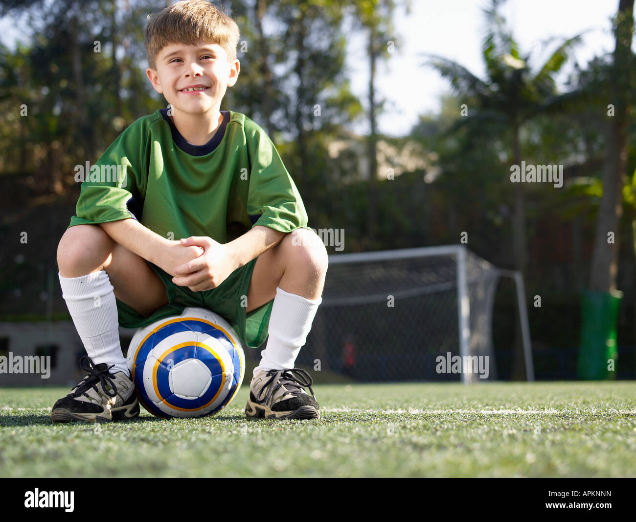 Boy sitting on soccer ball (portrait, low angle view Stock Photo - Alamy