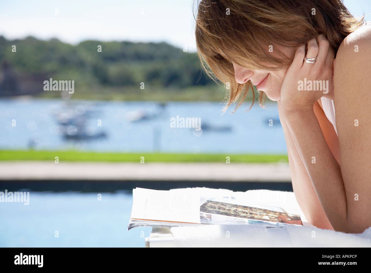 Woman reading by pool Stock Photo - Alamy