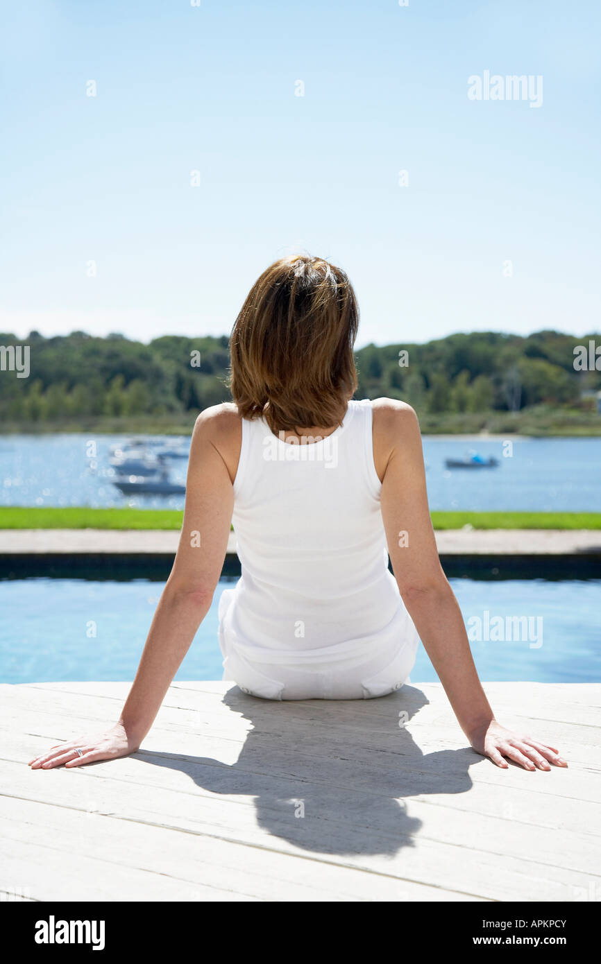 Woman sitting by pool Stock Photo - Alamy