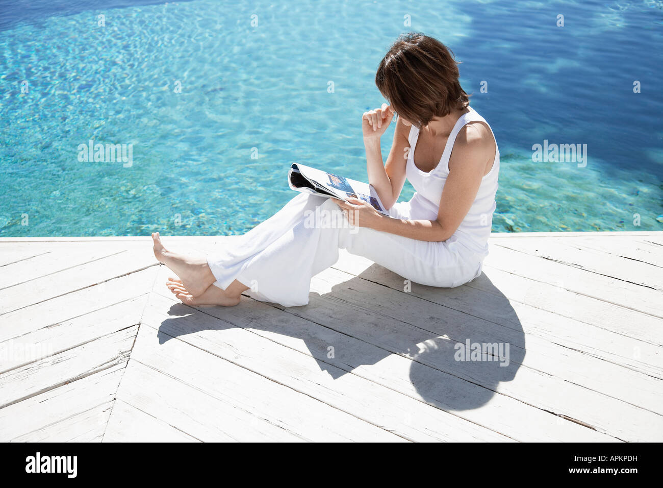 Woman reading magazine by pool (high angle view Stock Photo - Alamy
