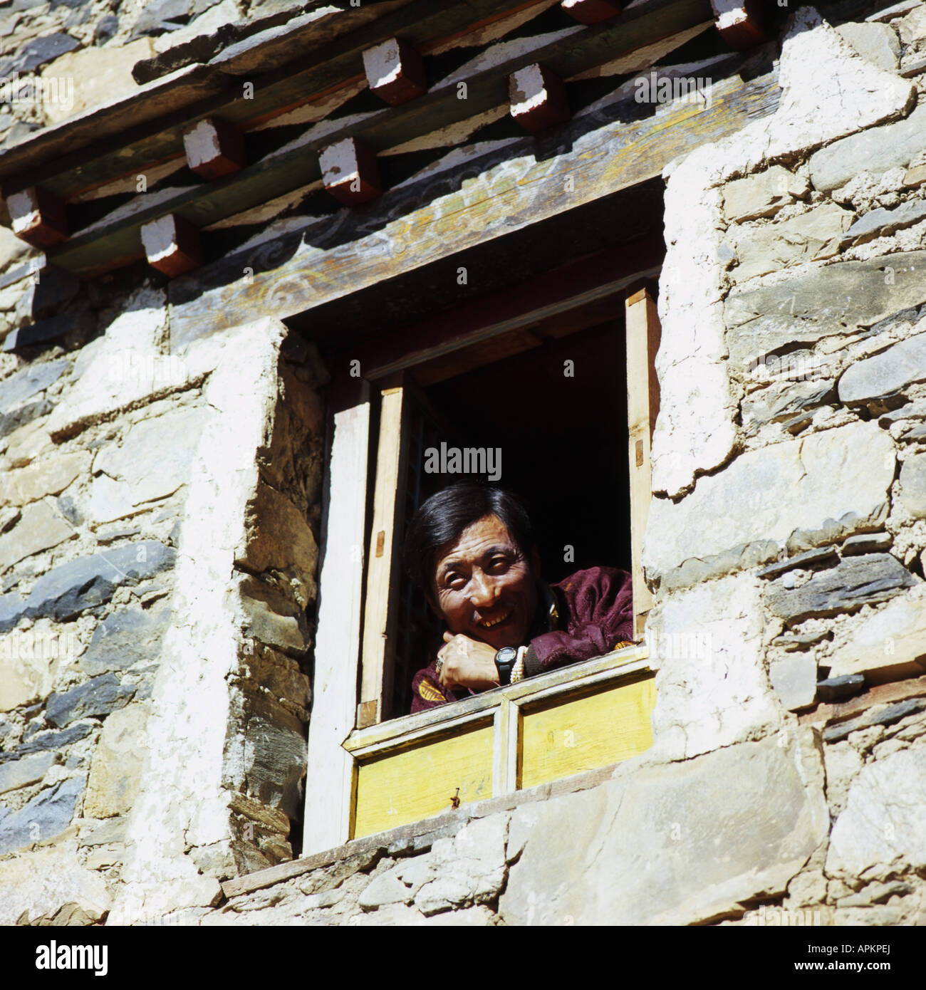 Tibetan looking out of the window of his traditional house, China ...