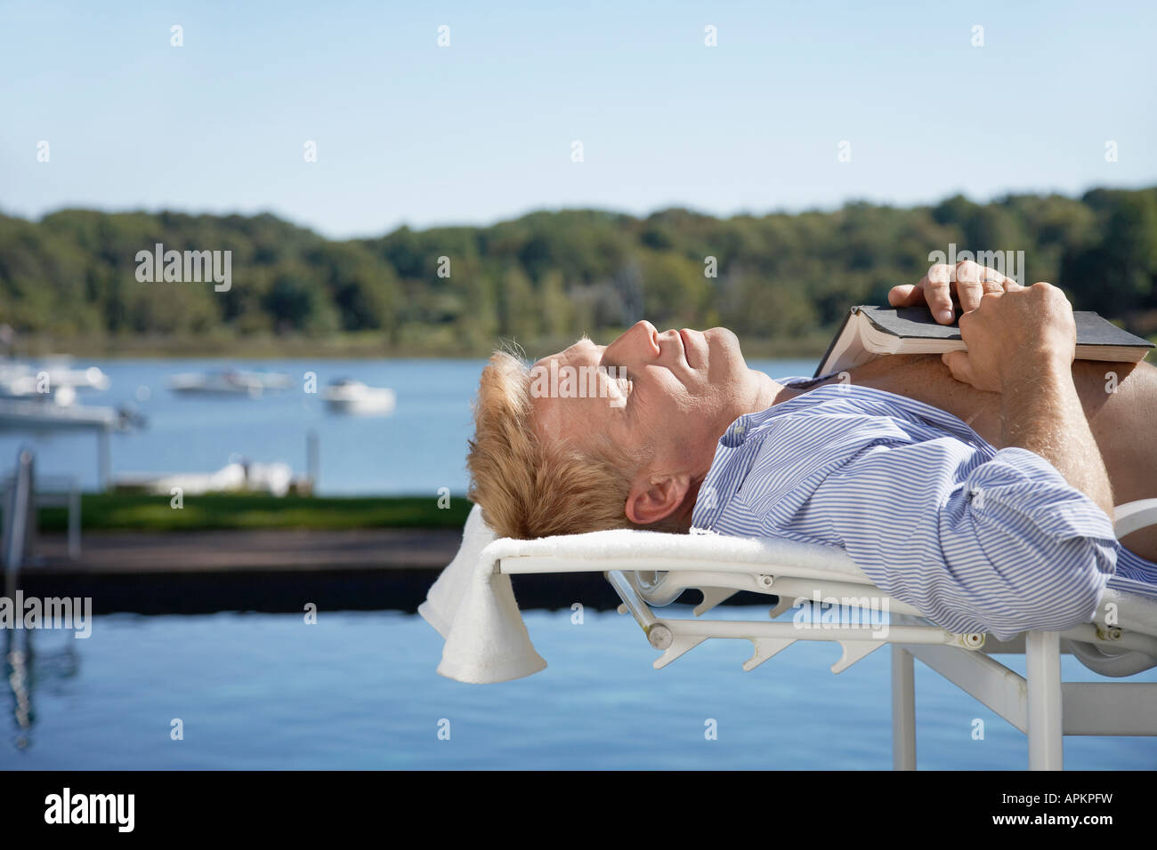 Man lying on lounge chair, book on chest Stock Photo - Alamy