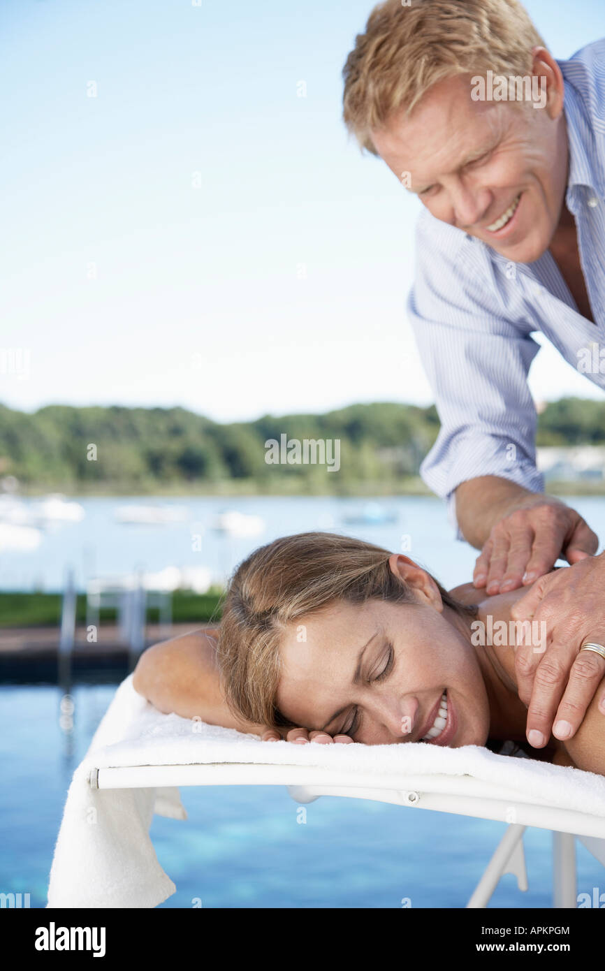 Man rubbing woman's back on lounge chair Stock Photo - Alamy