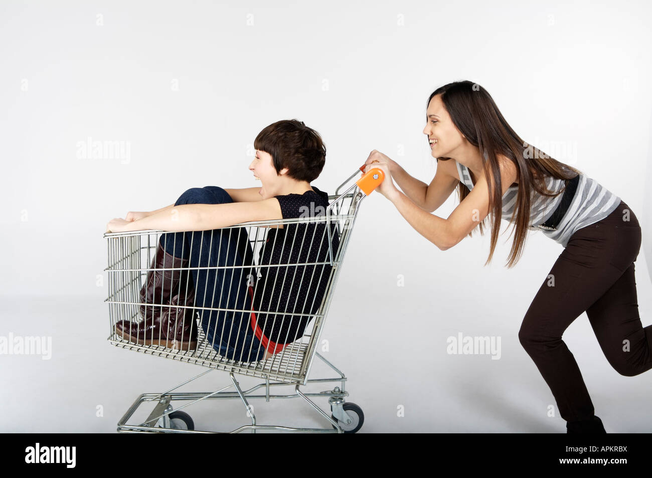 Two women playing with a grocery cart Stock Photo - Alamy