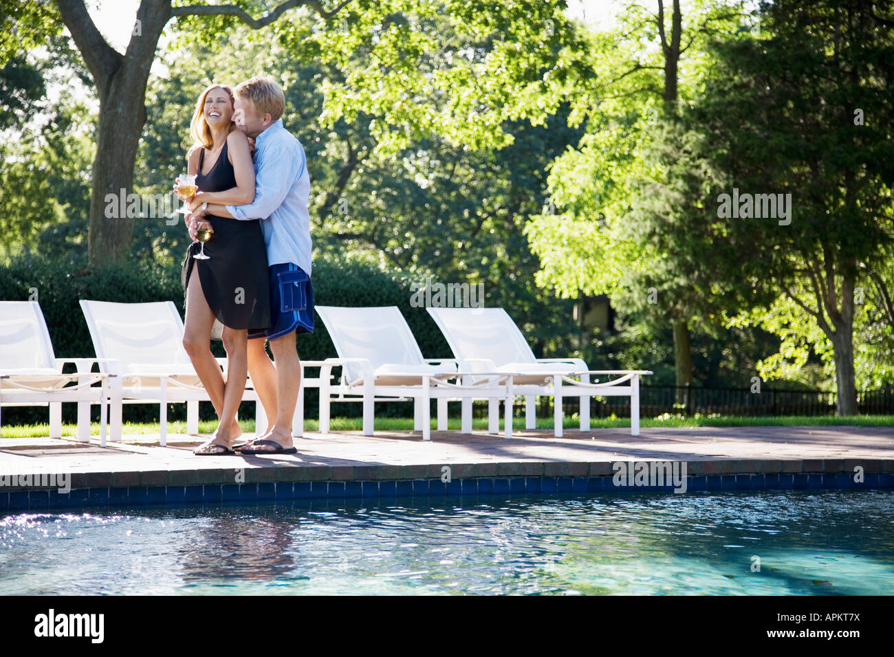 Couple hugging by pool Stock Photo - Alamy